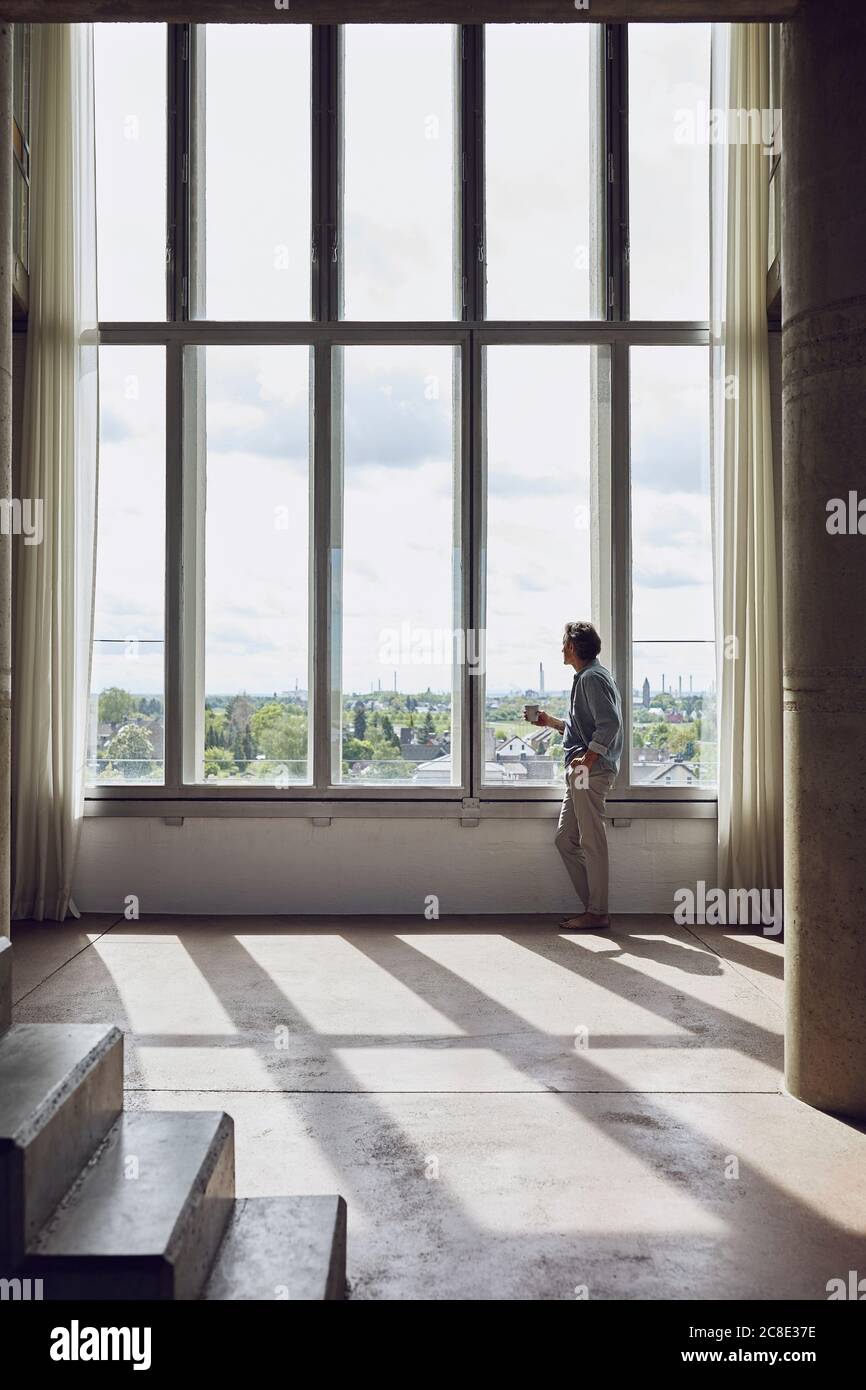 Senior man looking out of window in a loft flat Stock Photo - Alamy