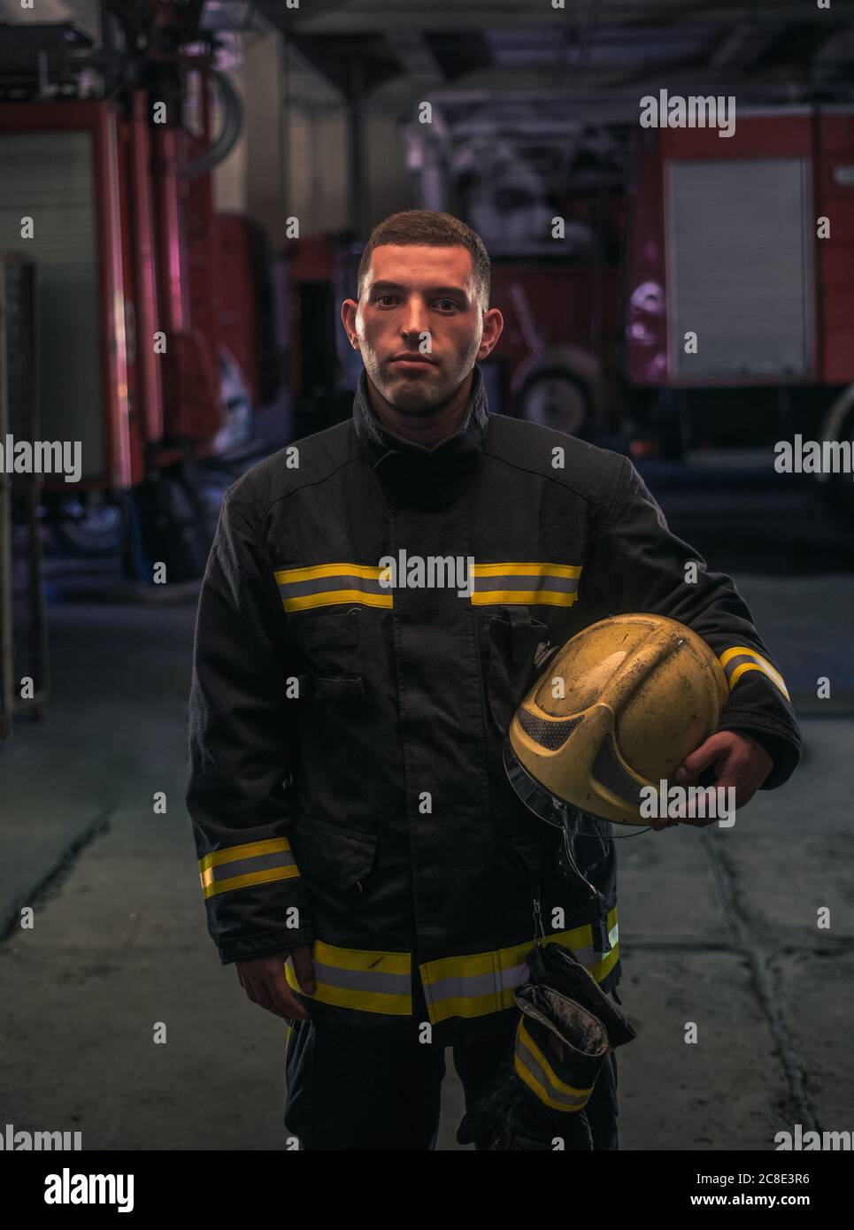 Portrait of young fireman standing inside the fire station Stock Photo ...