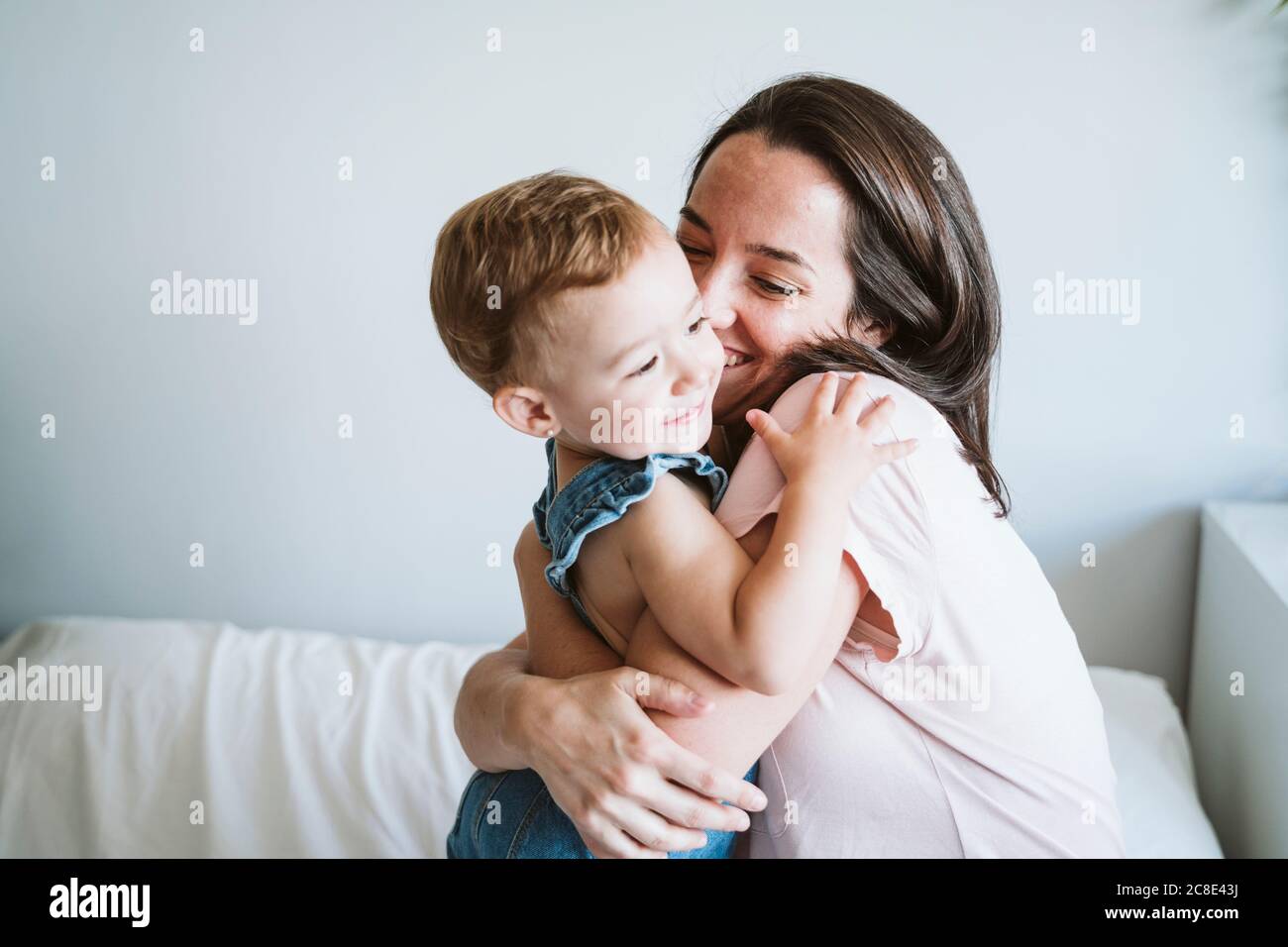 Mother hugging baby girl at home Stock Photo - Alamy