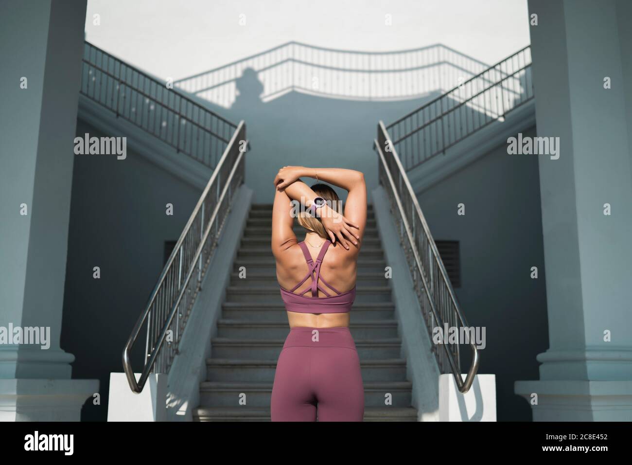 Young woman stretching arms while standing in front of steps Stock ...