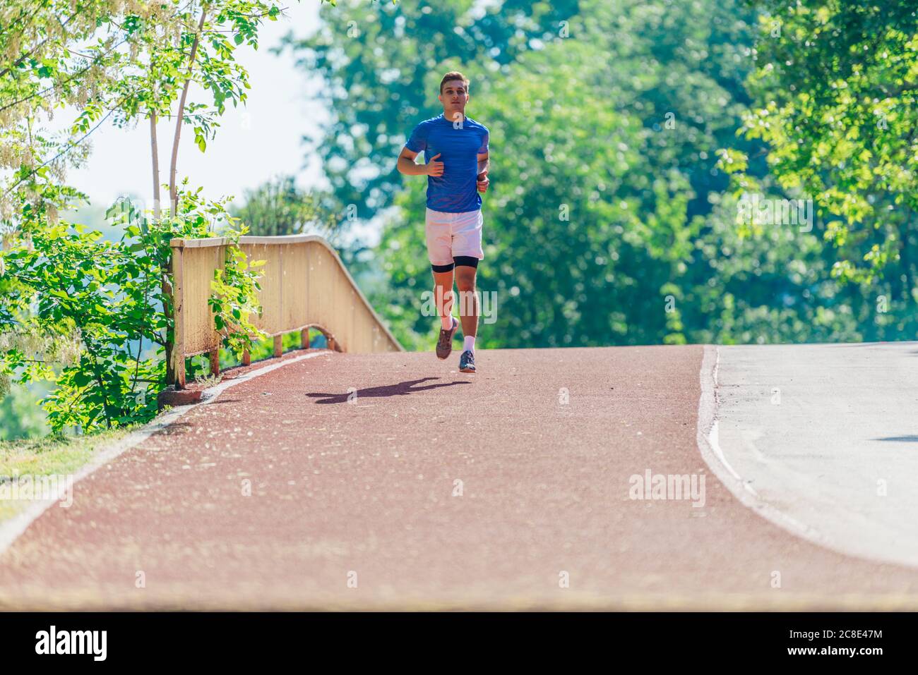 Athletic young man running on the race track in a sports park Stock ...