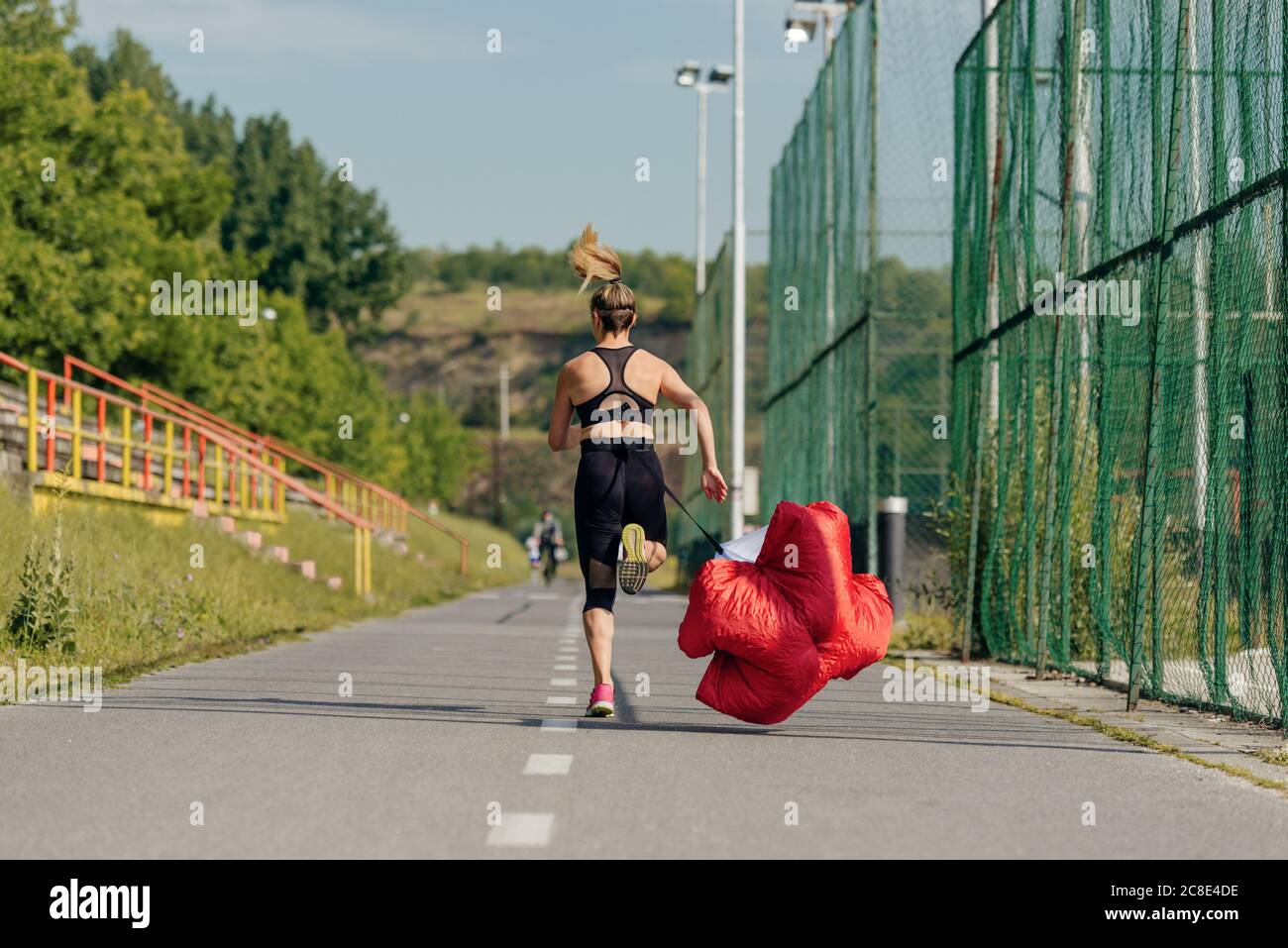 View from the back of a young female athlete running with a parachute ...