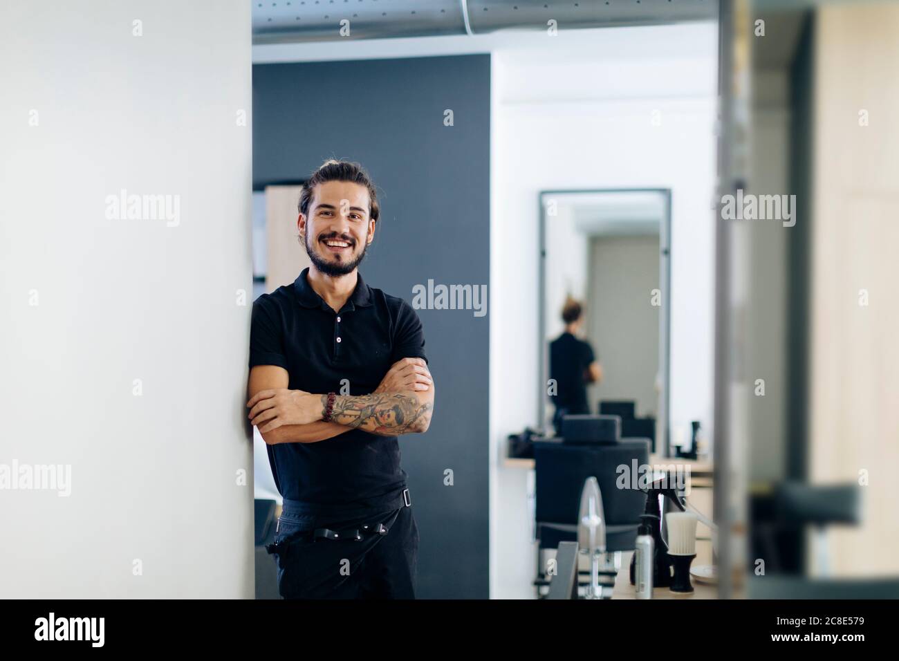 Confident male barber standing arms crossed in hair salon Stock Photo ...