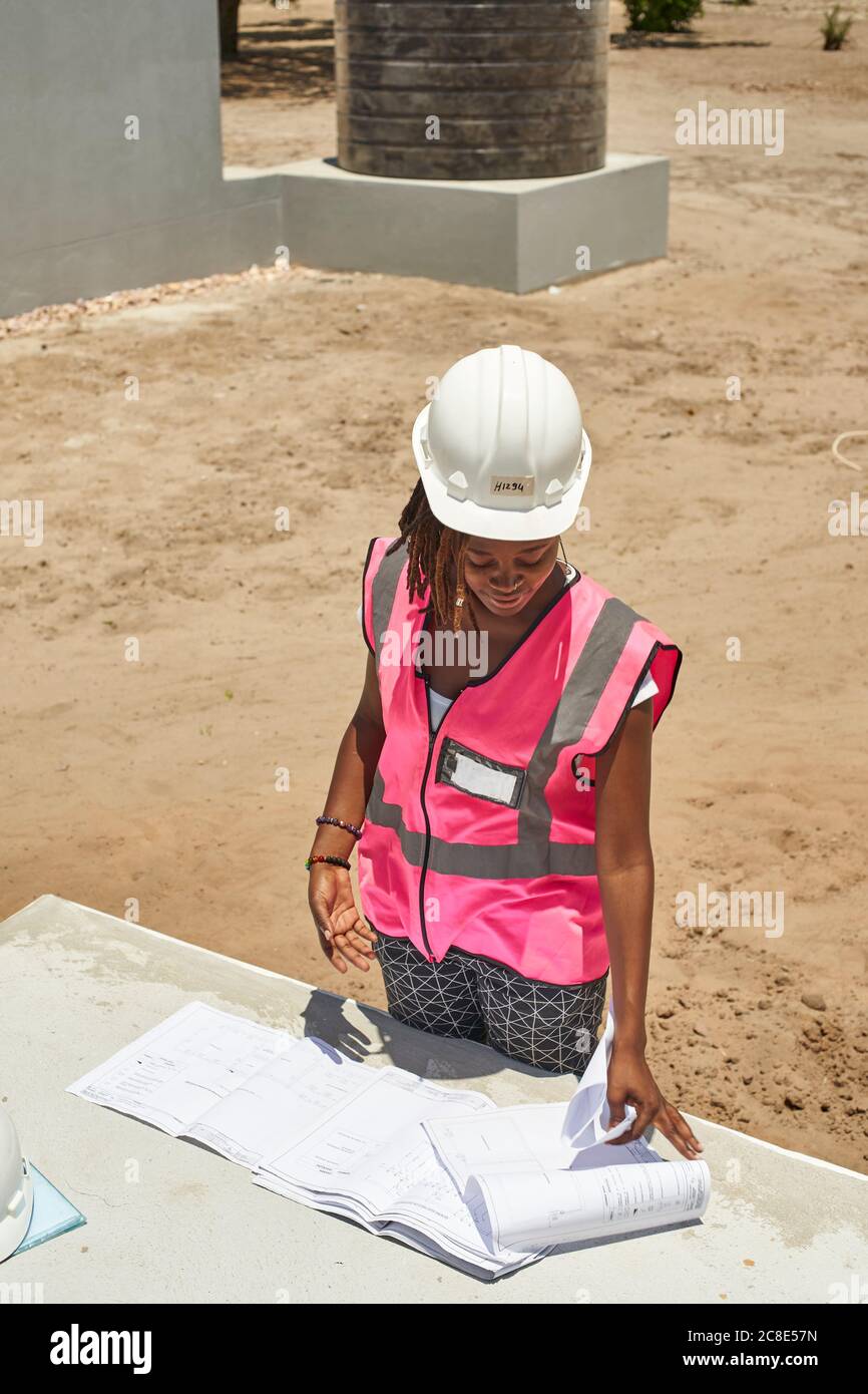 Female building contractor analyzing blueprint on table at construction ...