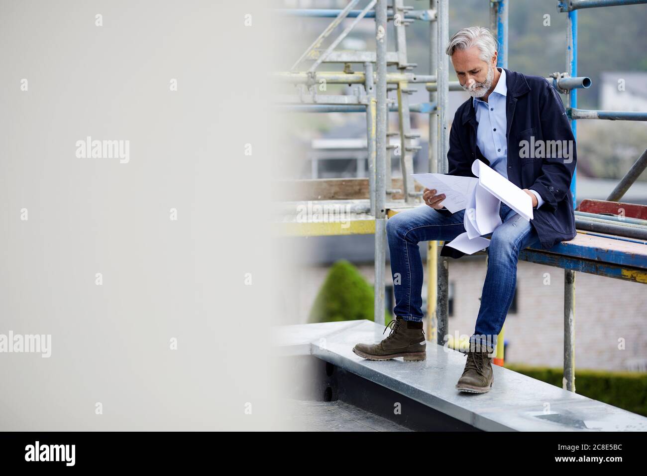 Architect looking at building plan on scaffolding on a construction ...