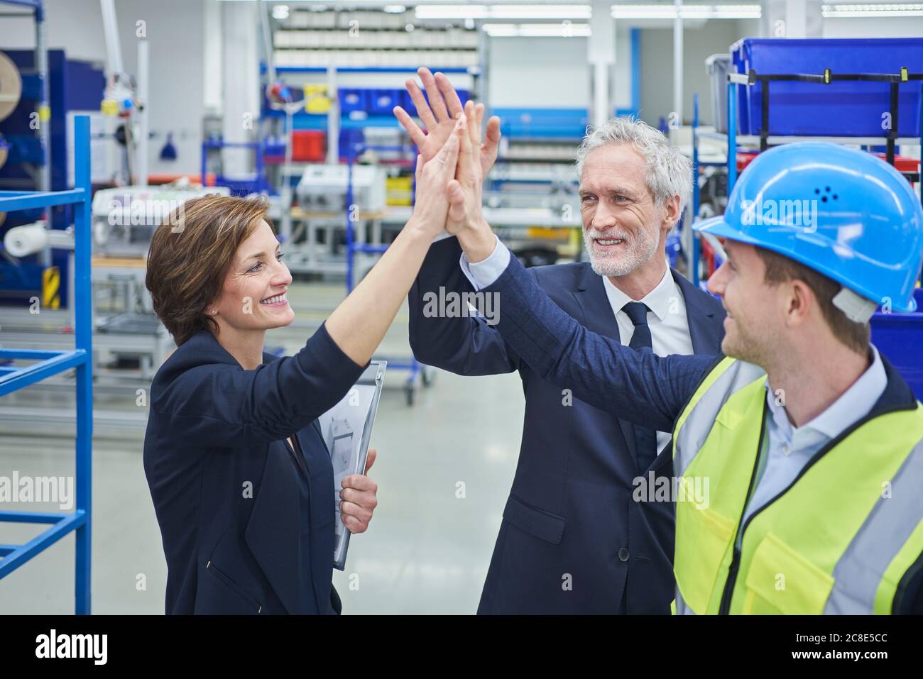Happy managers and supervisor giving high-five in factory Stock Photo ...