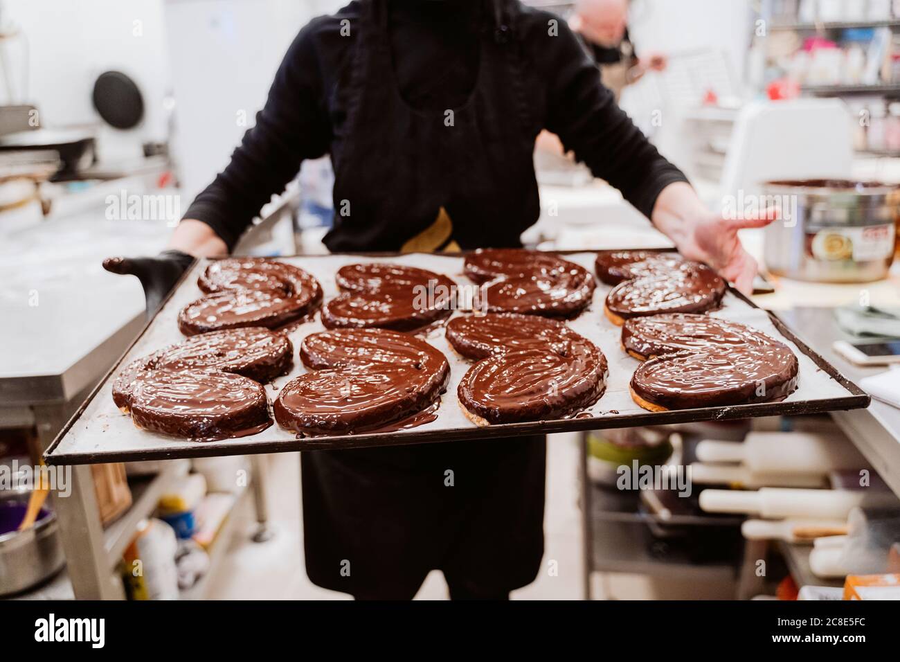 Female baker holding heart shaped dessert in baking tray at bakery ...