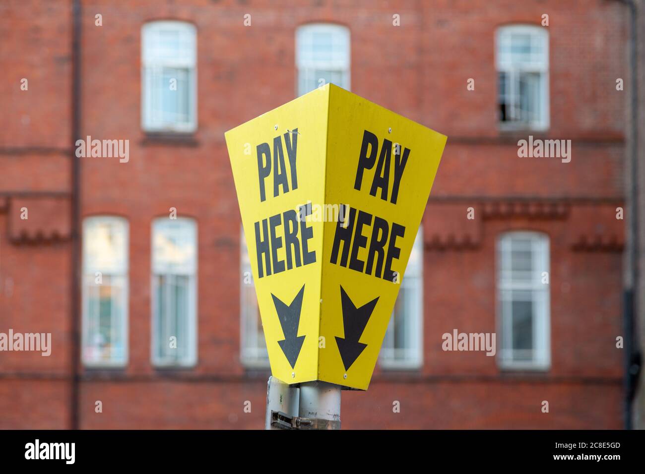 a pay here sign on top of a pay and display ticket car park machine ...