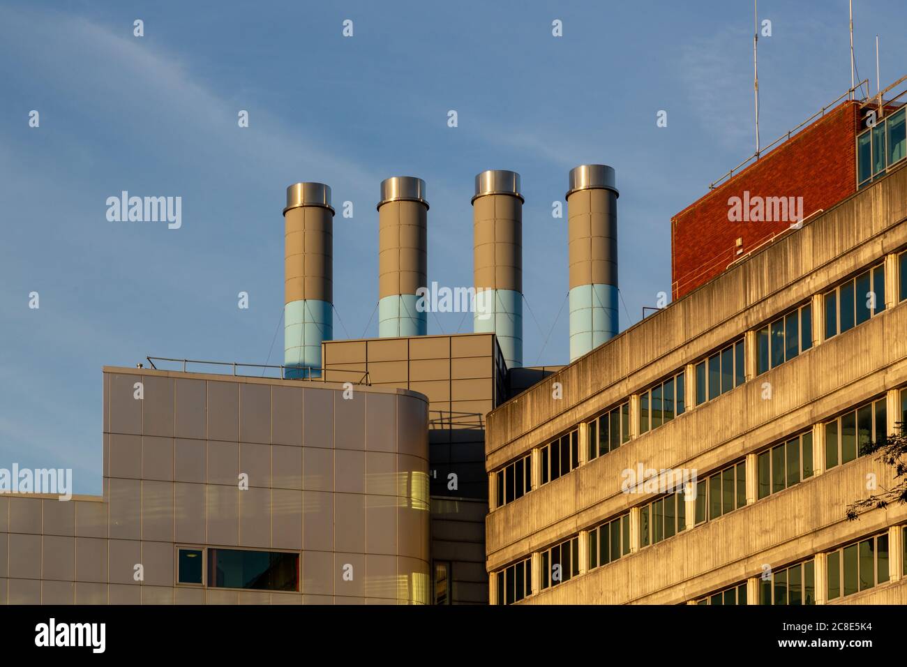 four industrial chimneys on top of a modern building Stock Photo - Alamy