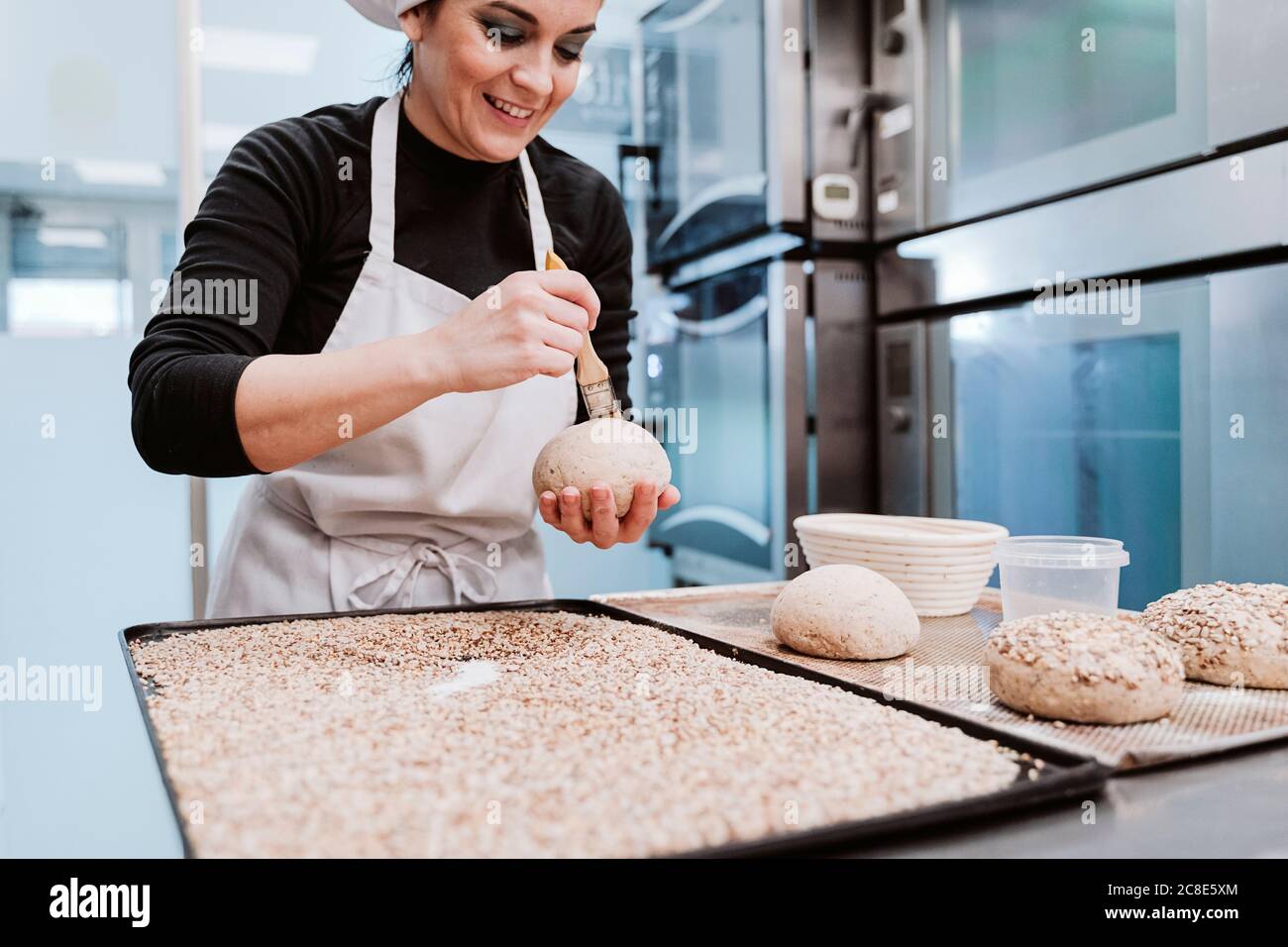 Female baker preparing wholegrain buns at bakery Stock Photo - Alamy