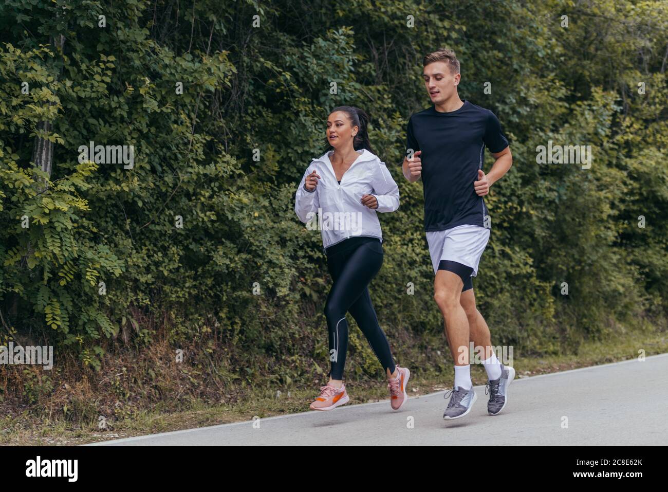 Athletic couple running on a street next to each other. Nature,fit and ...
