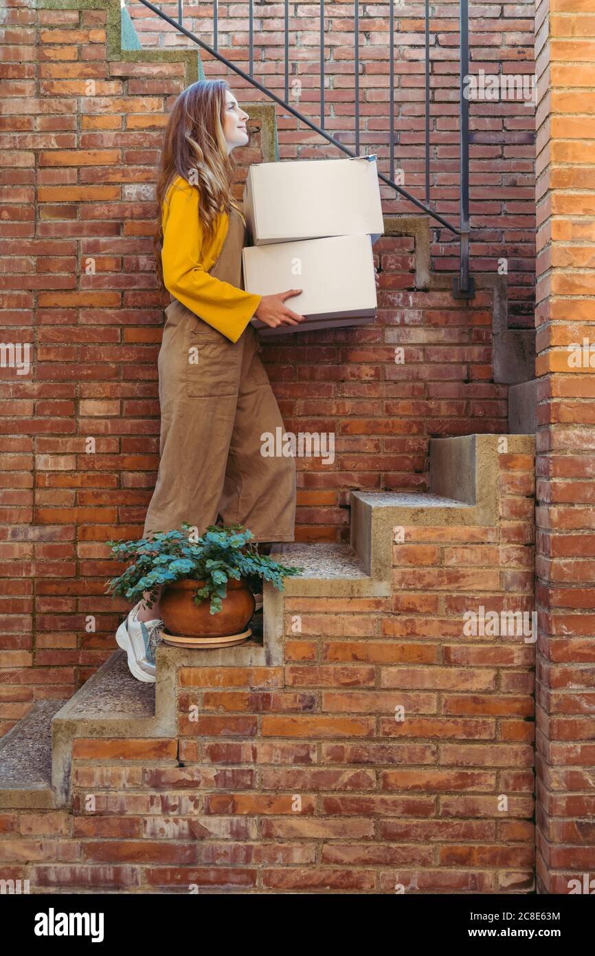 Young woman with white boxes moving up on steps by brick wall Stock ...