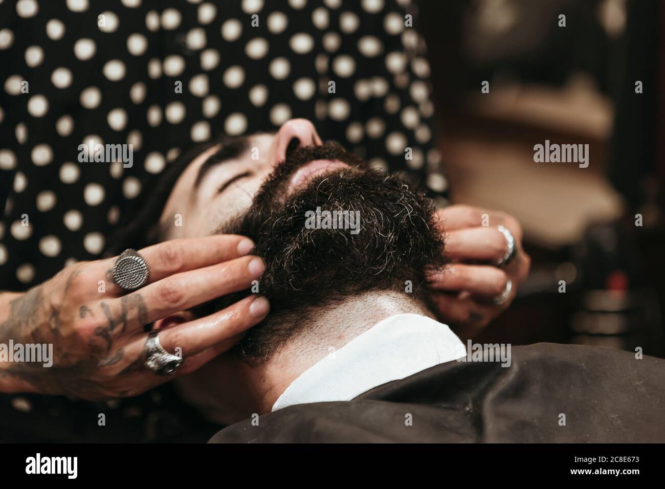 Barber styling client's beard at salon Stock Photo - Alamy