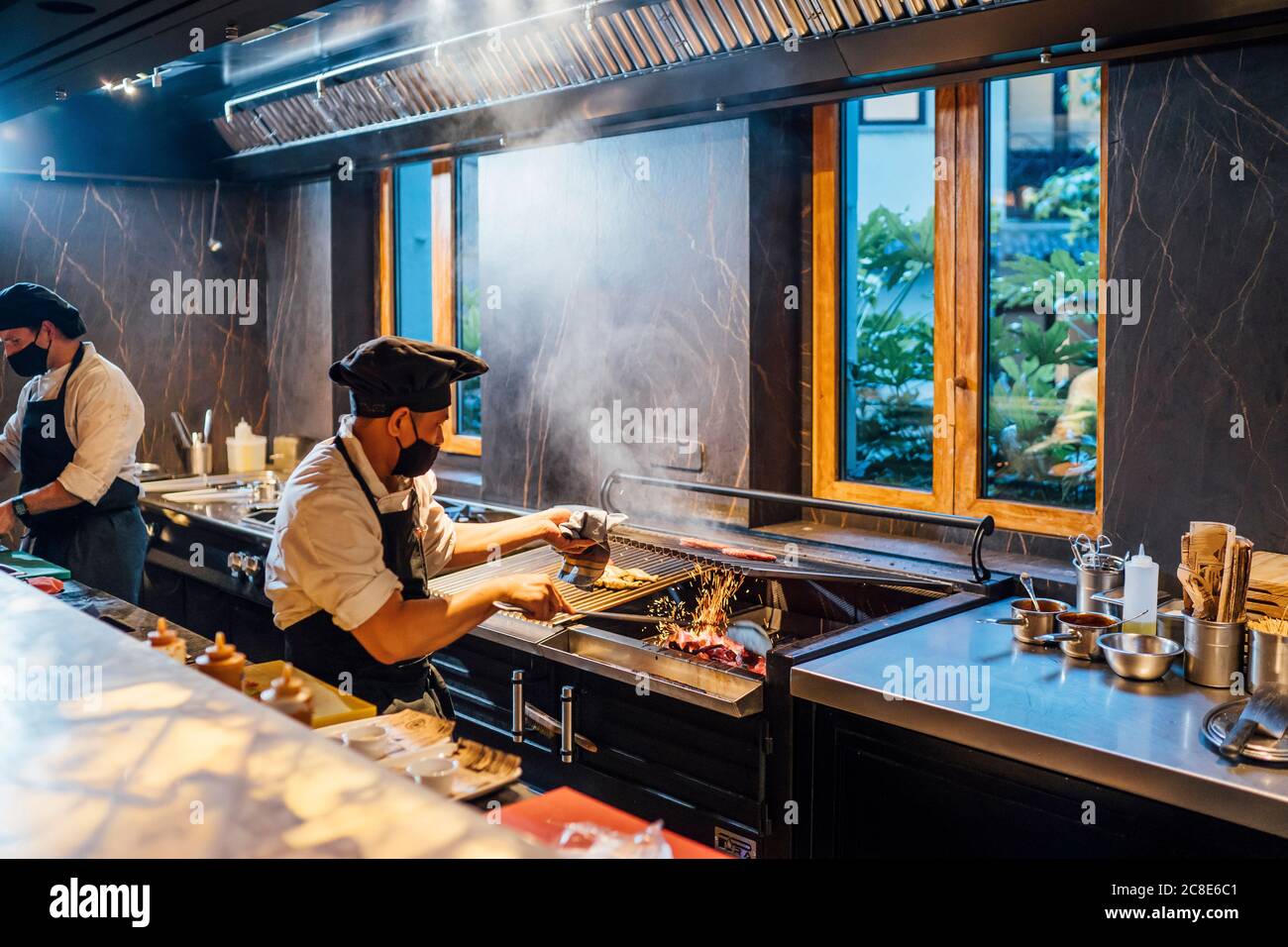 Chefs wearing protective face masks preparing a dish in restaurant ...