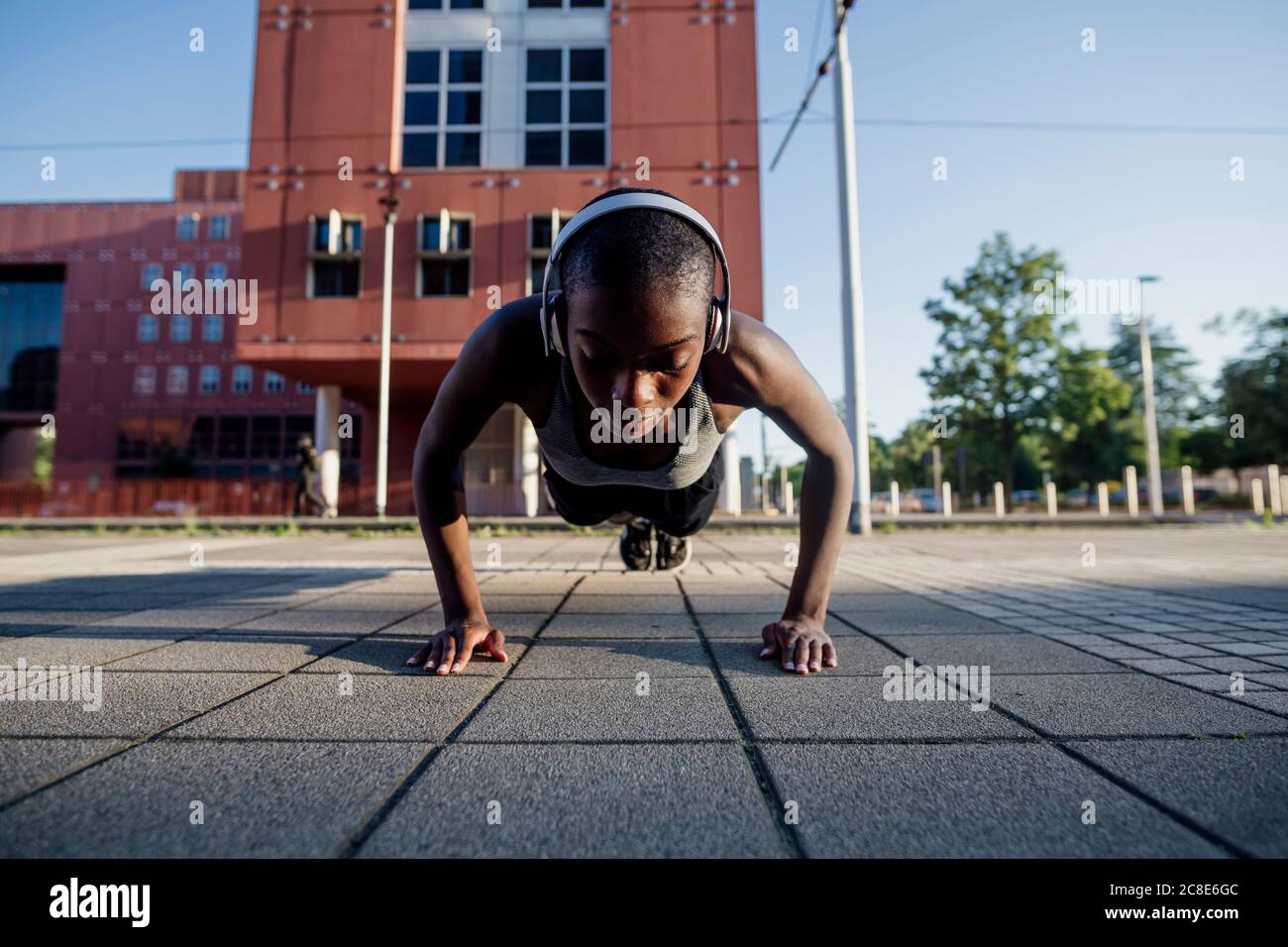 Female athlete with shaved head listening music through headphones ...