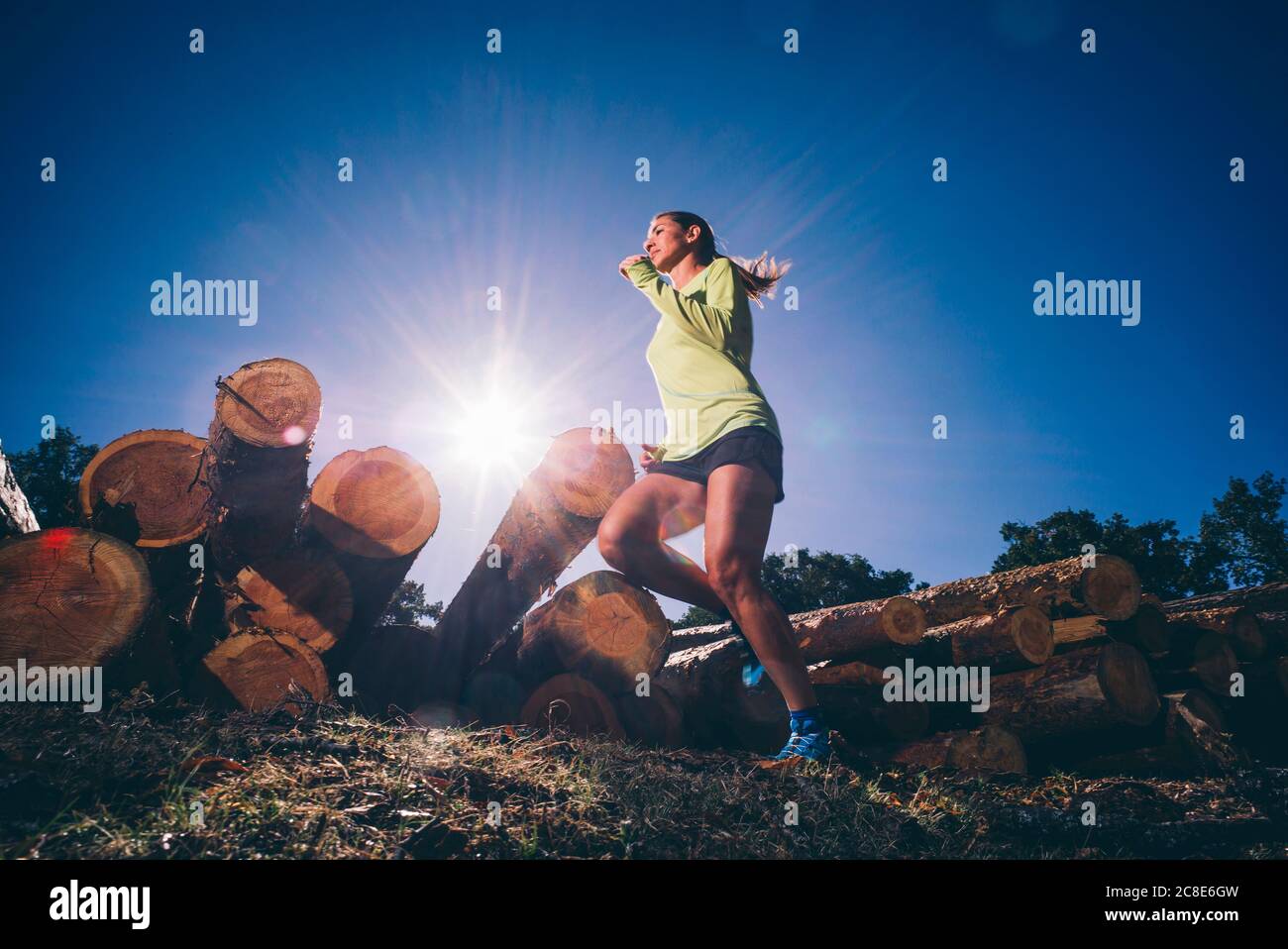 Mature woman running on land against clear blue sky during sunny day ...