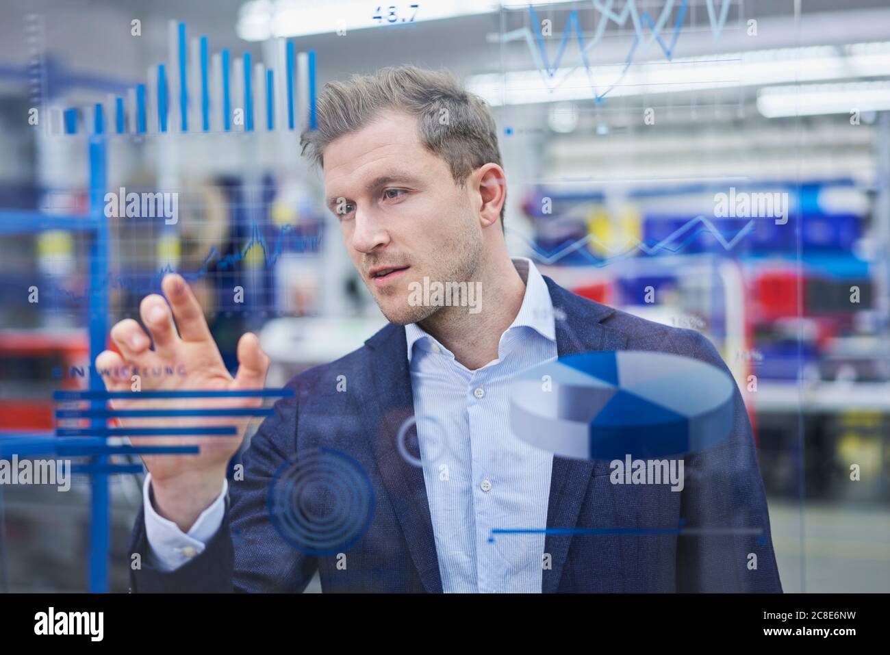 Male supervisor touching graphs on glass in industry Stock Photo - Alamy