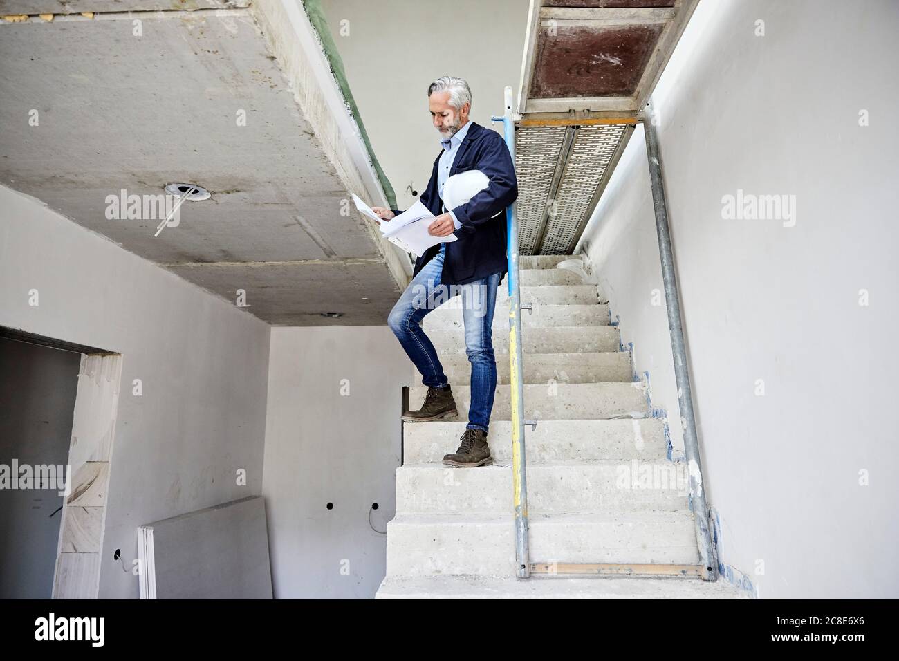 Architect holding building plan on a construction site Stock Photo - Alamy