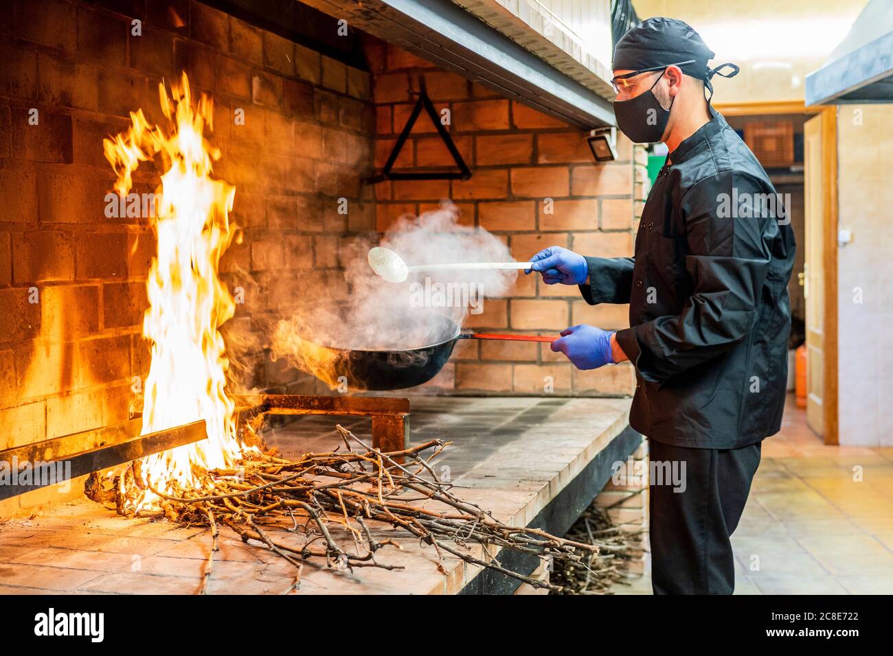 Traditional cooking of paella in restaurant kitchen, chef wearing ...