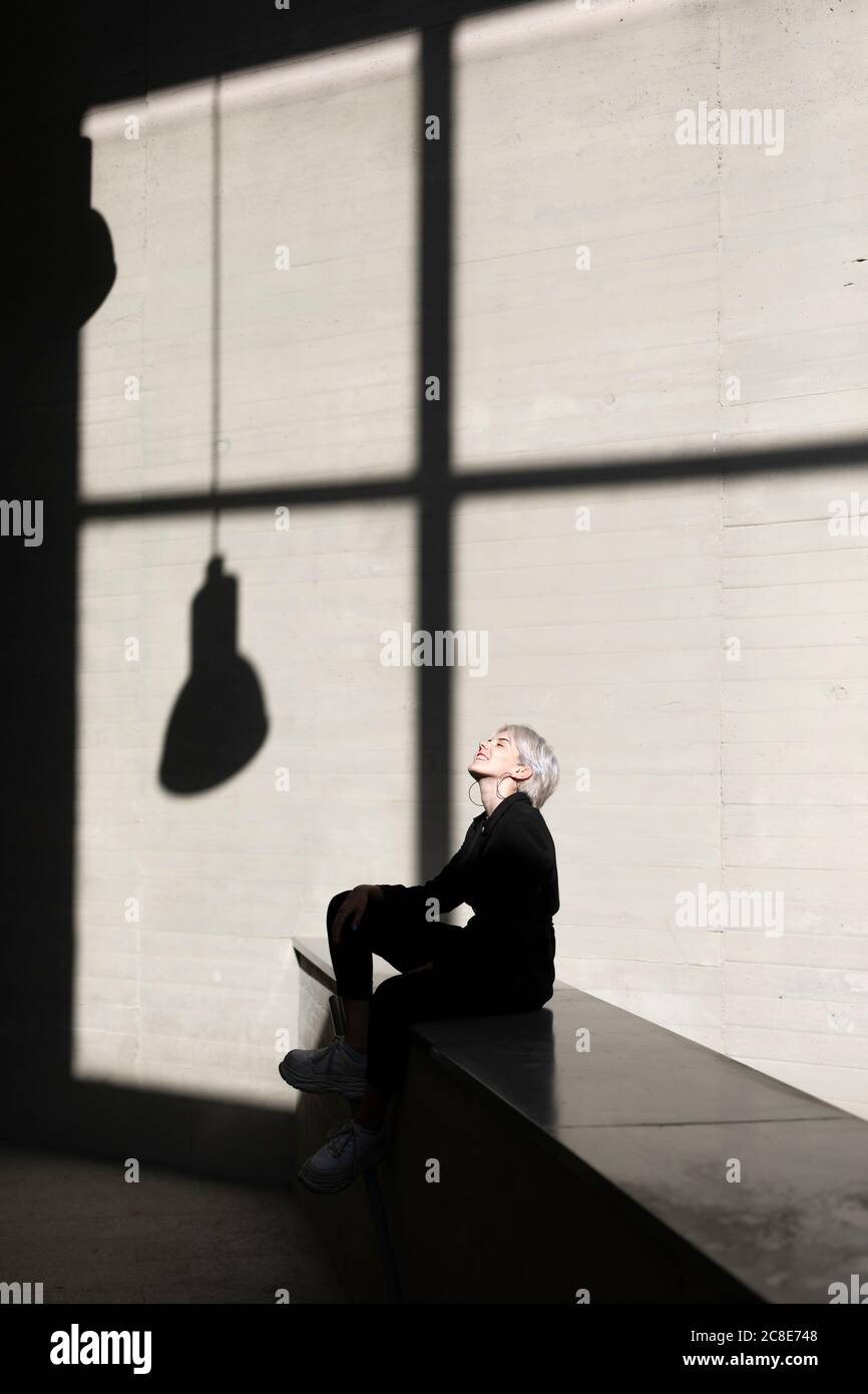 Young woman wearing elegant suit sitting with sunlight and shadow in ...