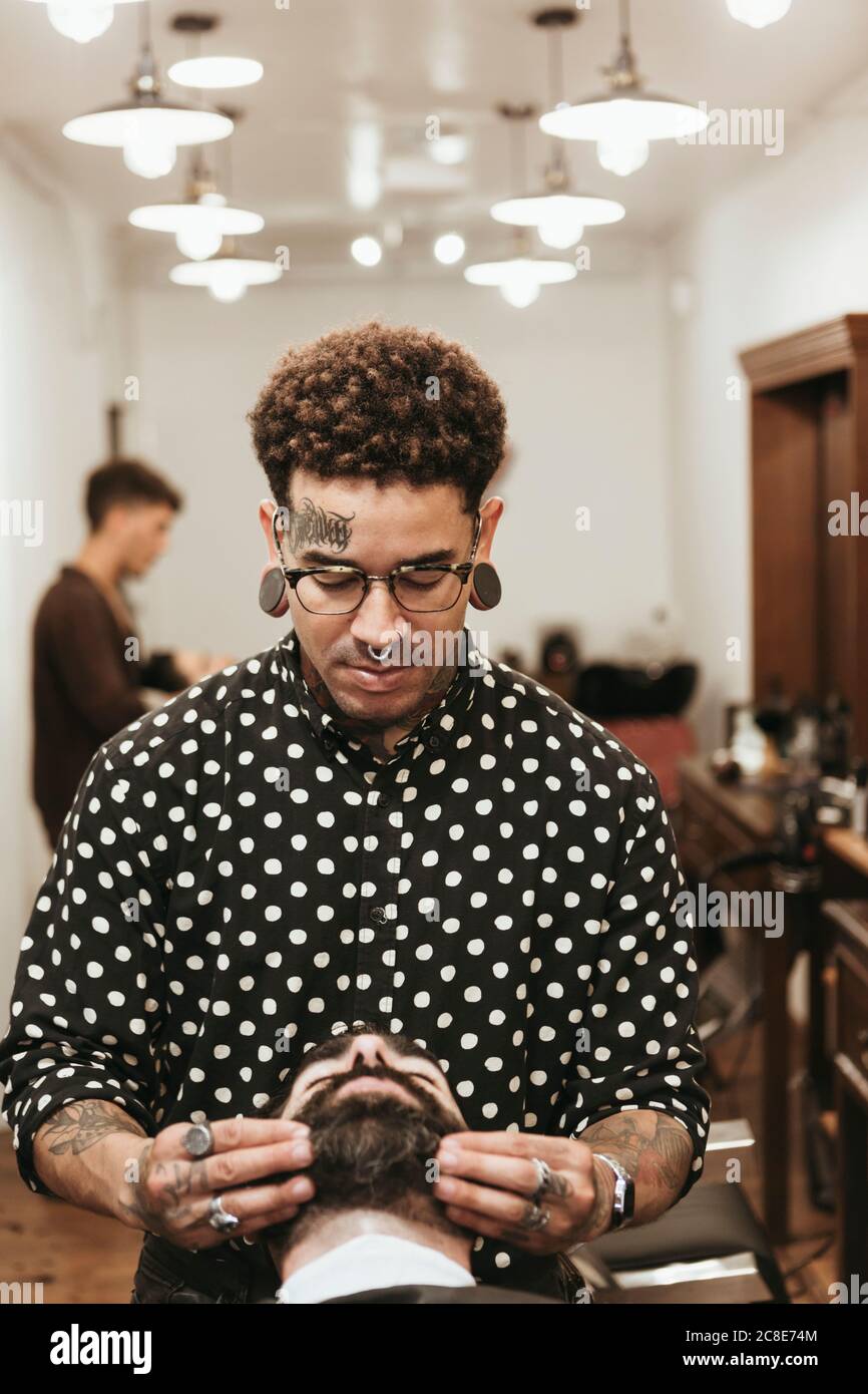 Trendy barber styling client's beard at salon Stock Photo - Alamy