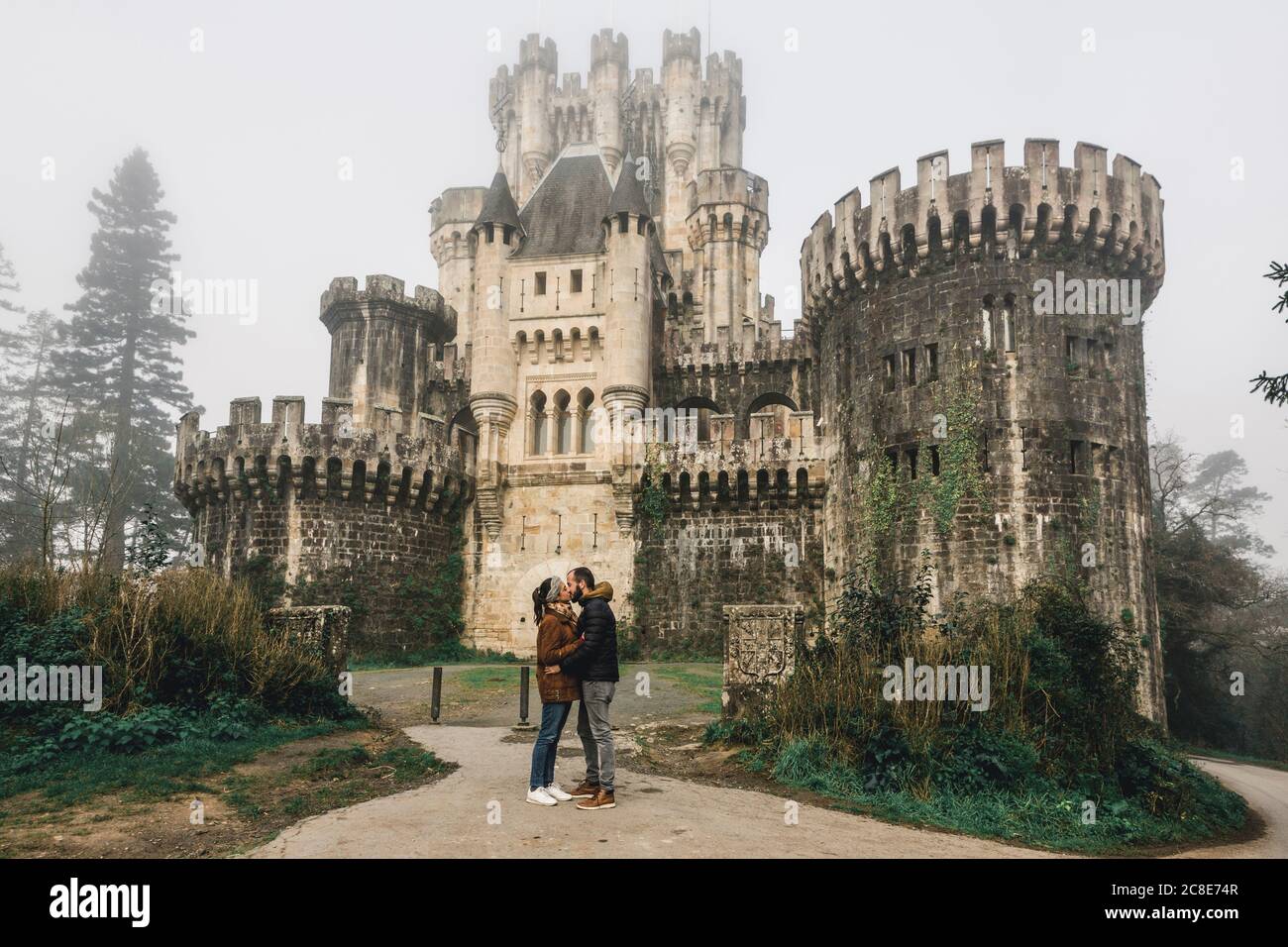 Couple kissing while standing against Butron Castle, Basque Country ...