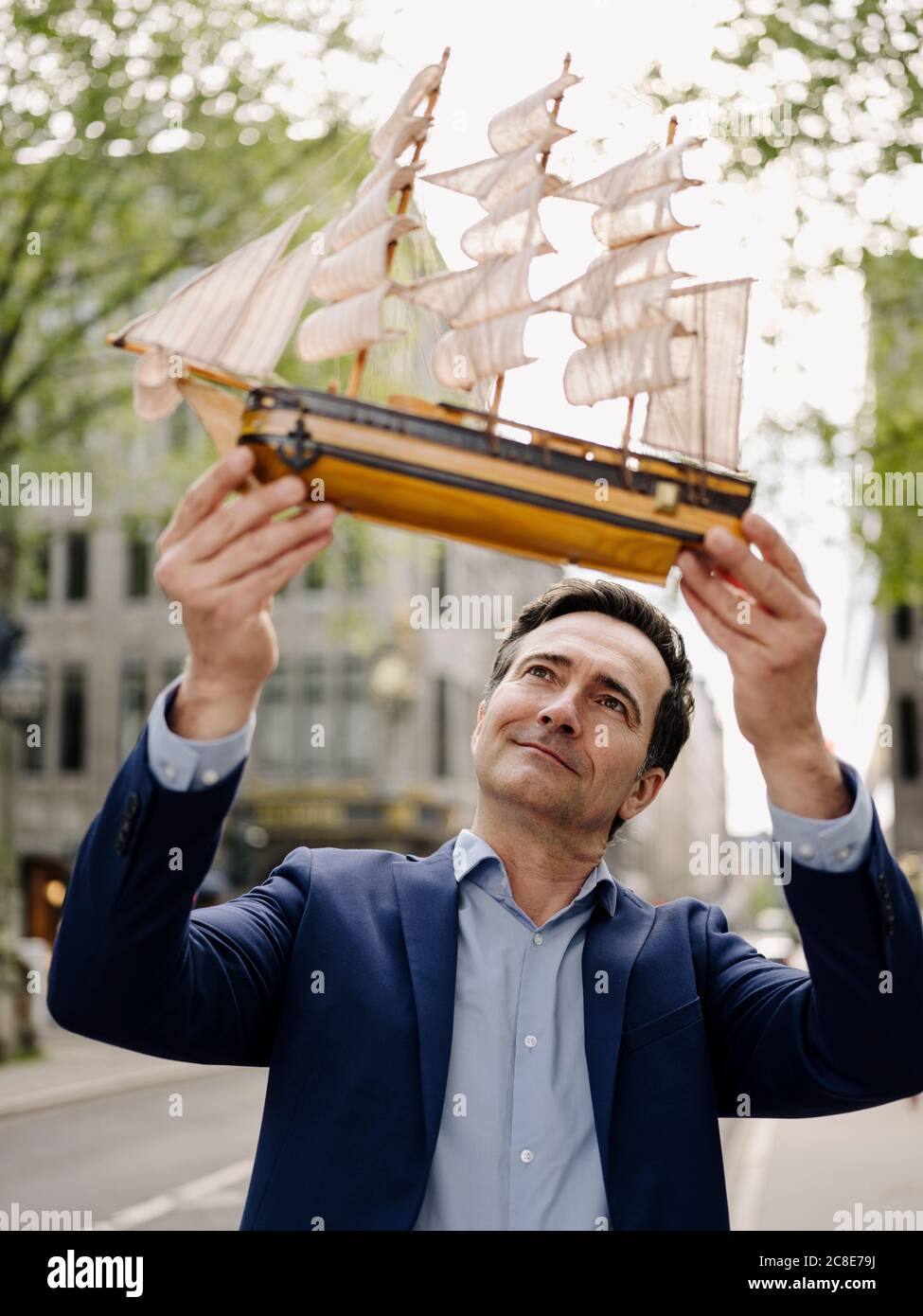 Mature businessman holding model sailing ship in the city Stock Photo ...