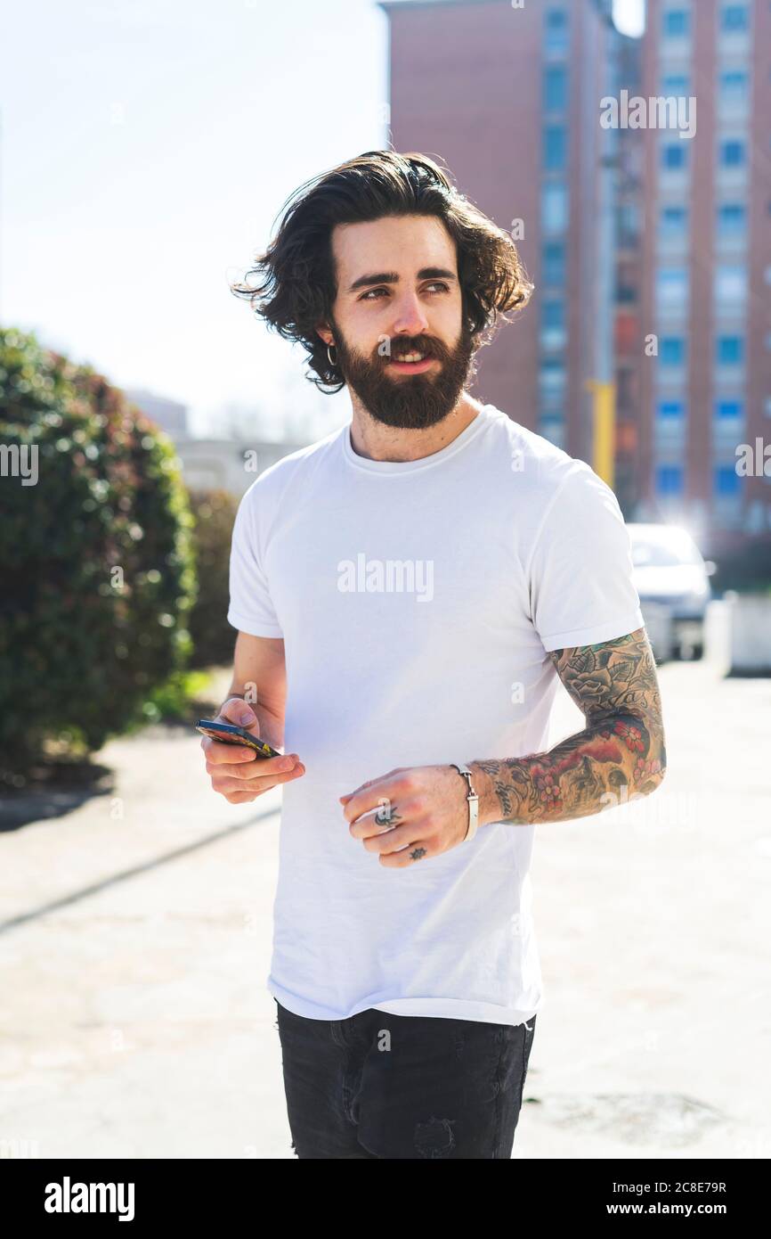 Young caucasian man walking on a beach at golden hour wearing a t-shirt ...