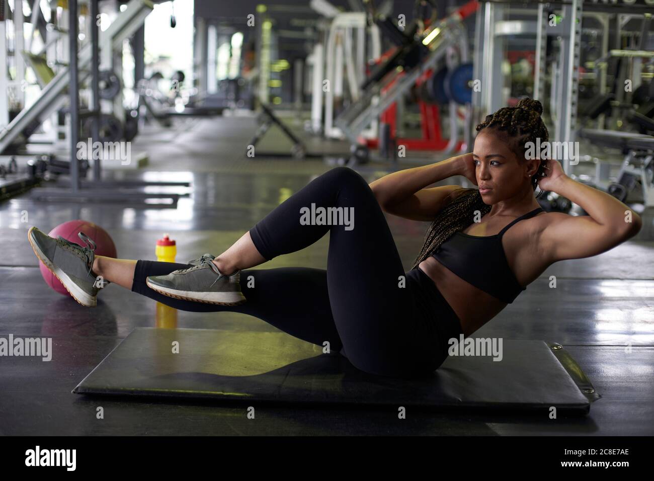 Female athlete with hands behind head doing abdominal exercise on mat ...