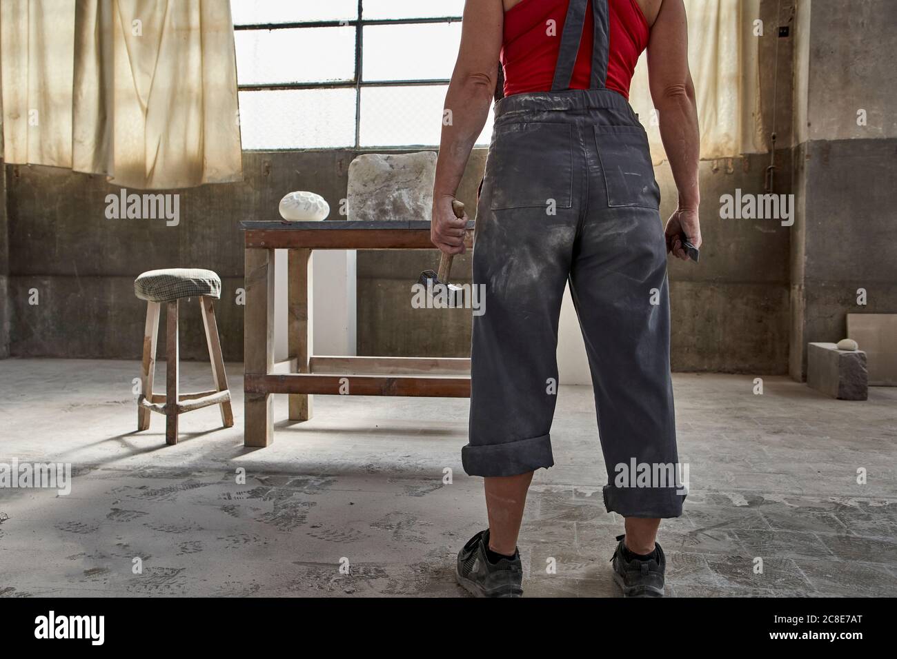 Female stonemason holding work tools standing in front of table at ...