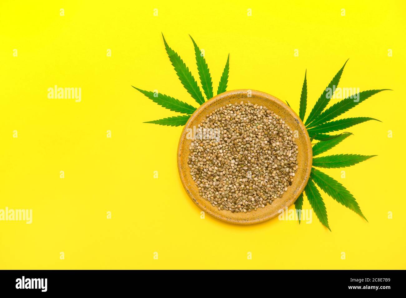 Green cannabis leaf and seeds on plate on yellow background. Vegetarian ...