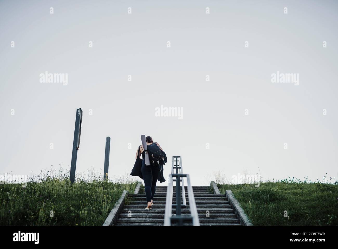 Sporty young woman moving up steps against clear sky Stock Photo - Alamy