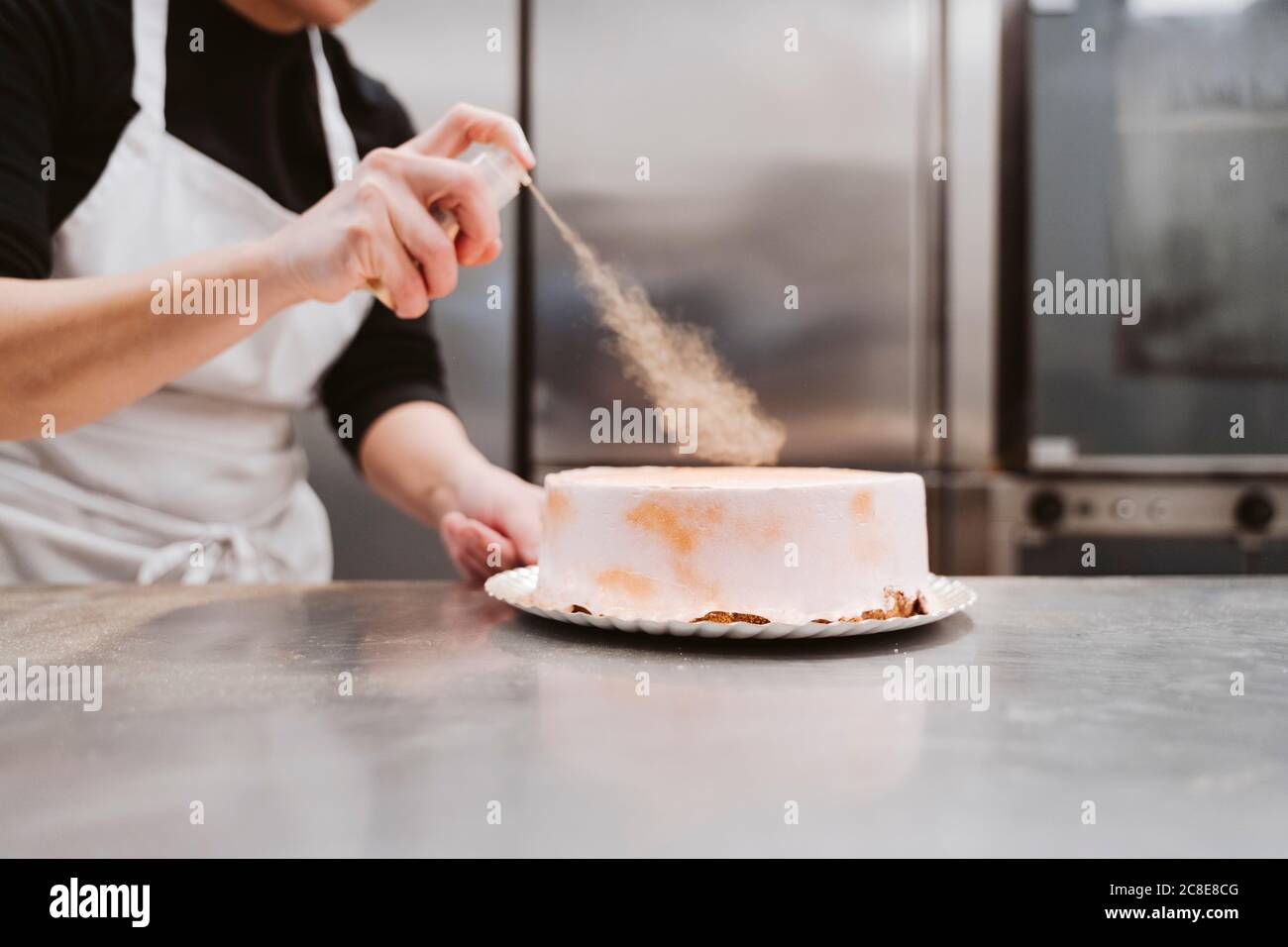 Female baker spraying cream on cake in bakery Stock Photo - Alamy