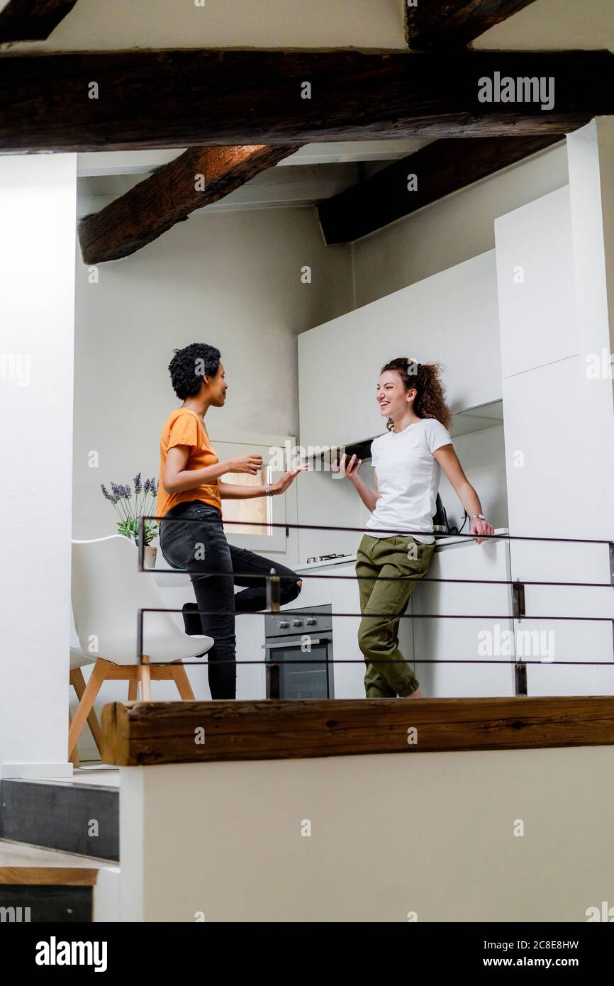 Two friends talking together in kitchen Stock Photo - Alamy