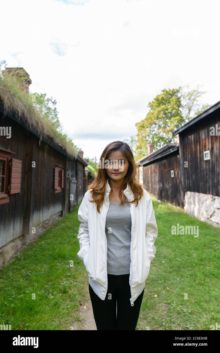 Young beautiful Asian woman in the middle of aligned old wooden ...