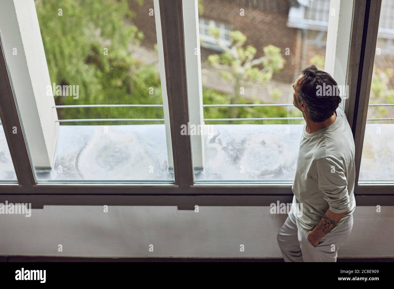 Senior man looking out of window in a loft flat Stock Photo - Alamy