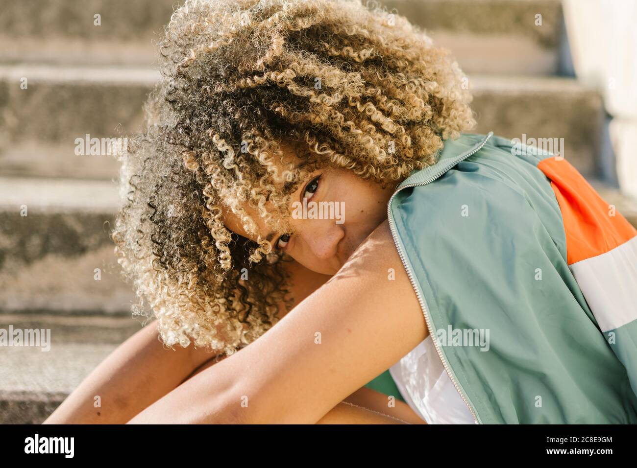 Confident young woman sitting on steps during sunny day Stock Photo - Alamy
