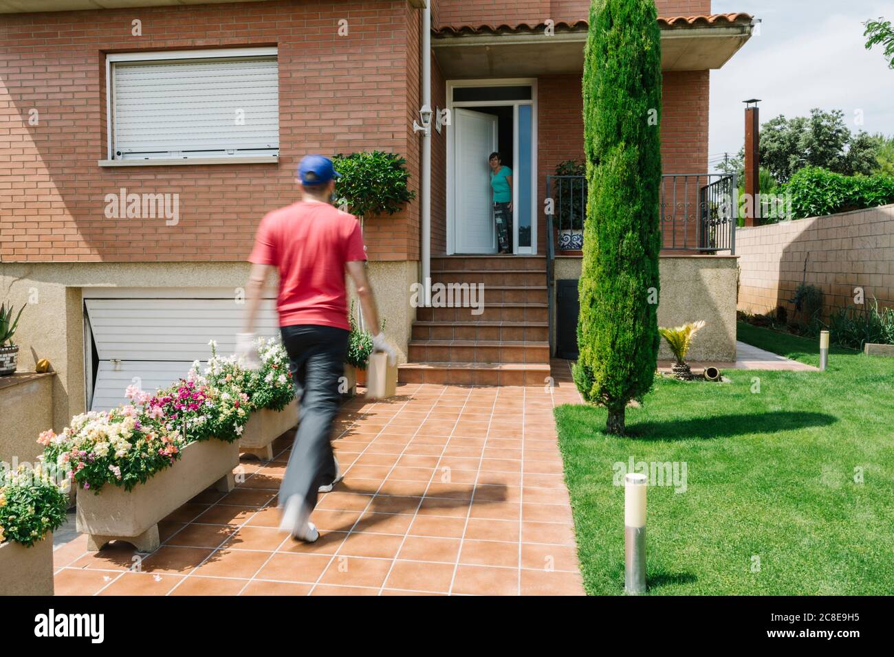 Woman waiting for postal worker to deliver her package Stock Photo - Alamy