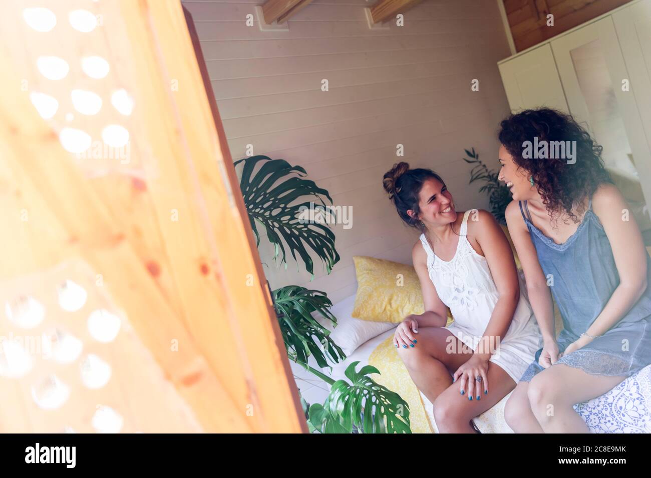 Happy young female friends talking in cottage seen through window Stock ...