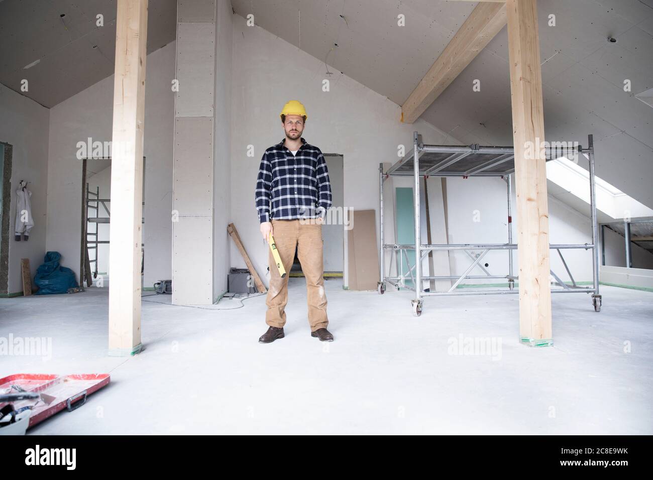 Confident construction worker standing at renovating home Stock Photo - Alamy