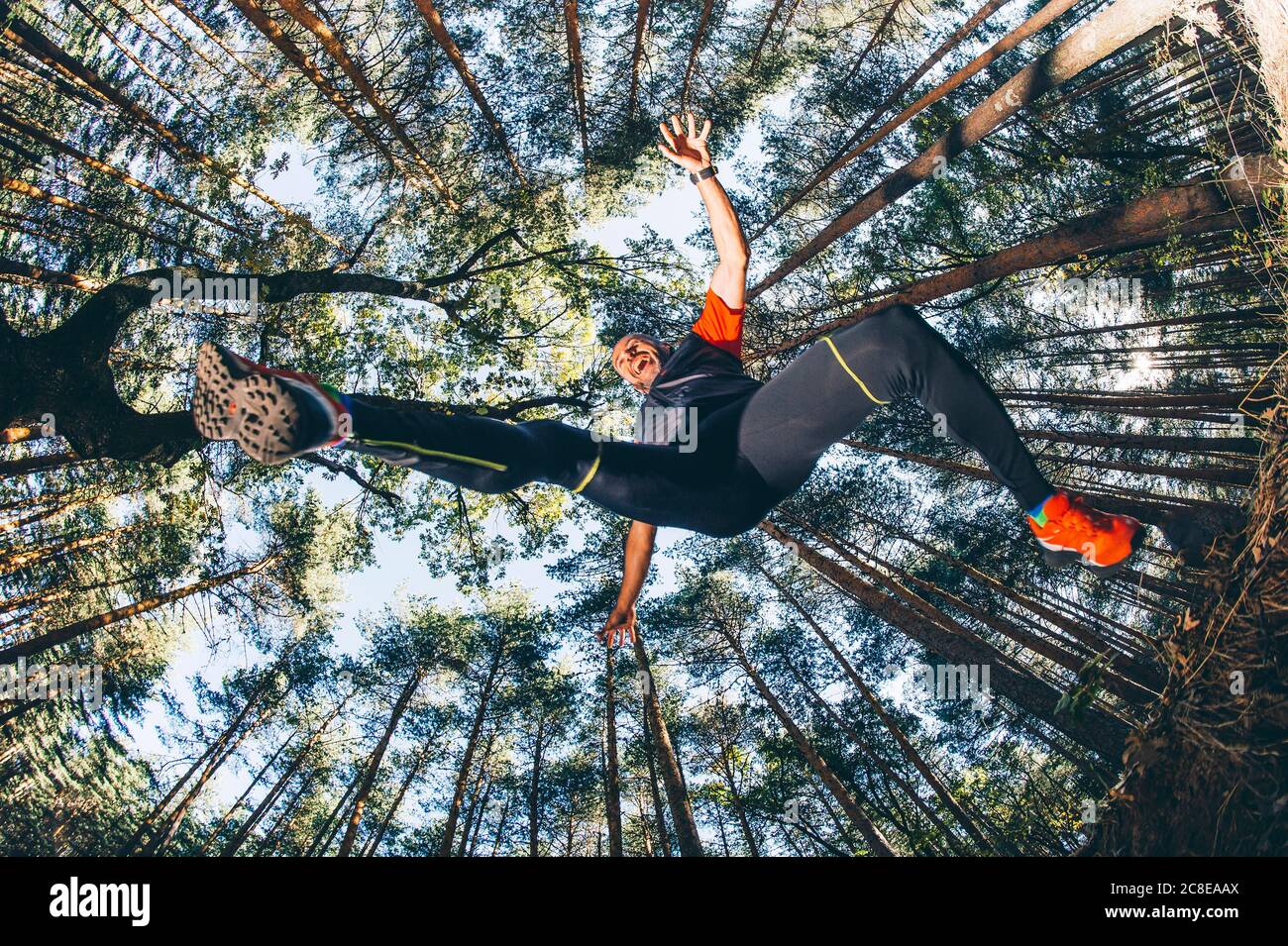 Mature man jumping against trees in forest Stock Photo - Alamy