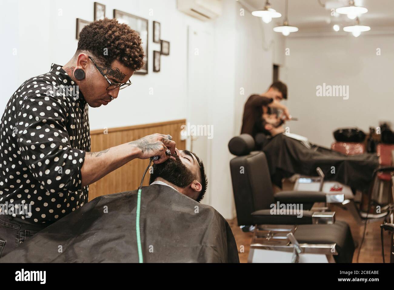 Trendy barber styling client's beard at salon Stock Photo - Alamy