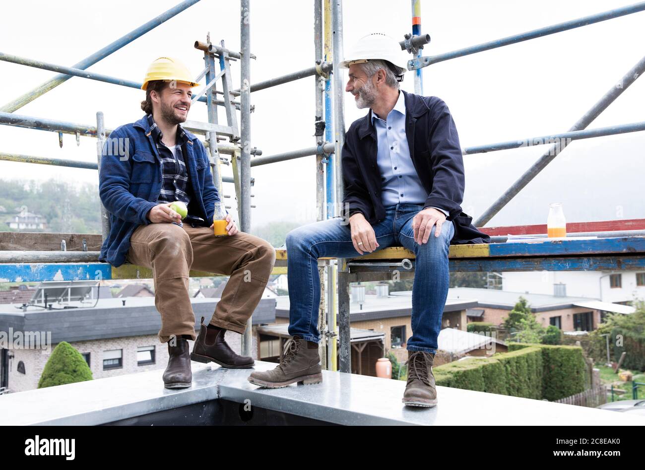 Architect and construction worker talking while sitting at construction ...