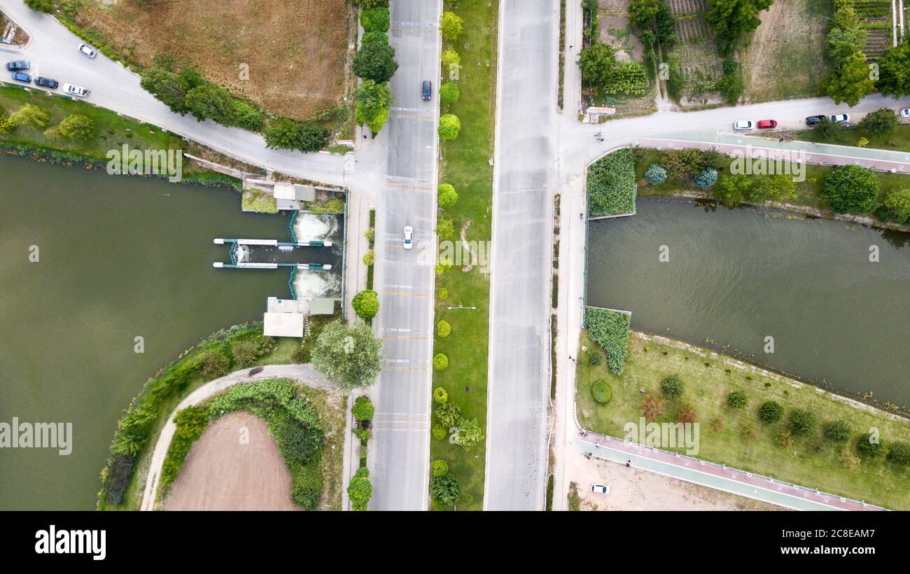 Aerial view of the double lane road on the river. Agriculture fields ...