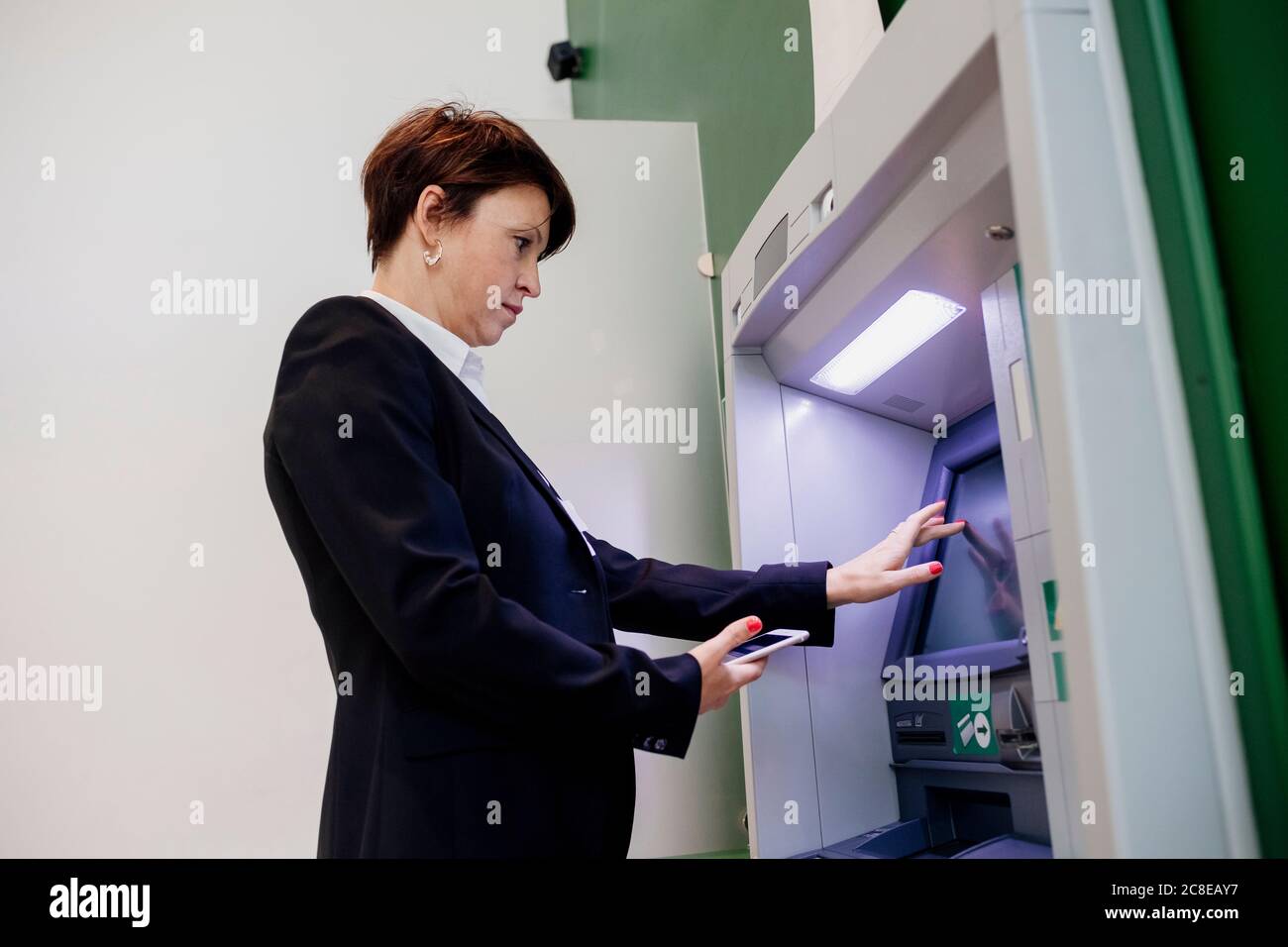 Withdrawing money at the atm with phone hi-res stock photography and ...