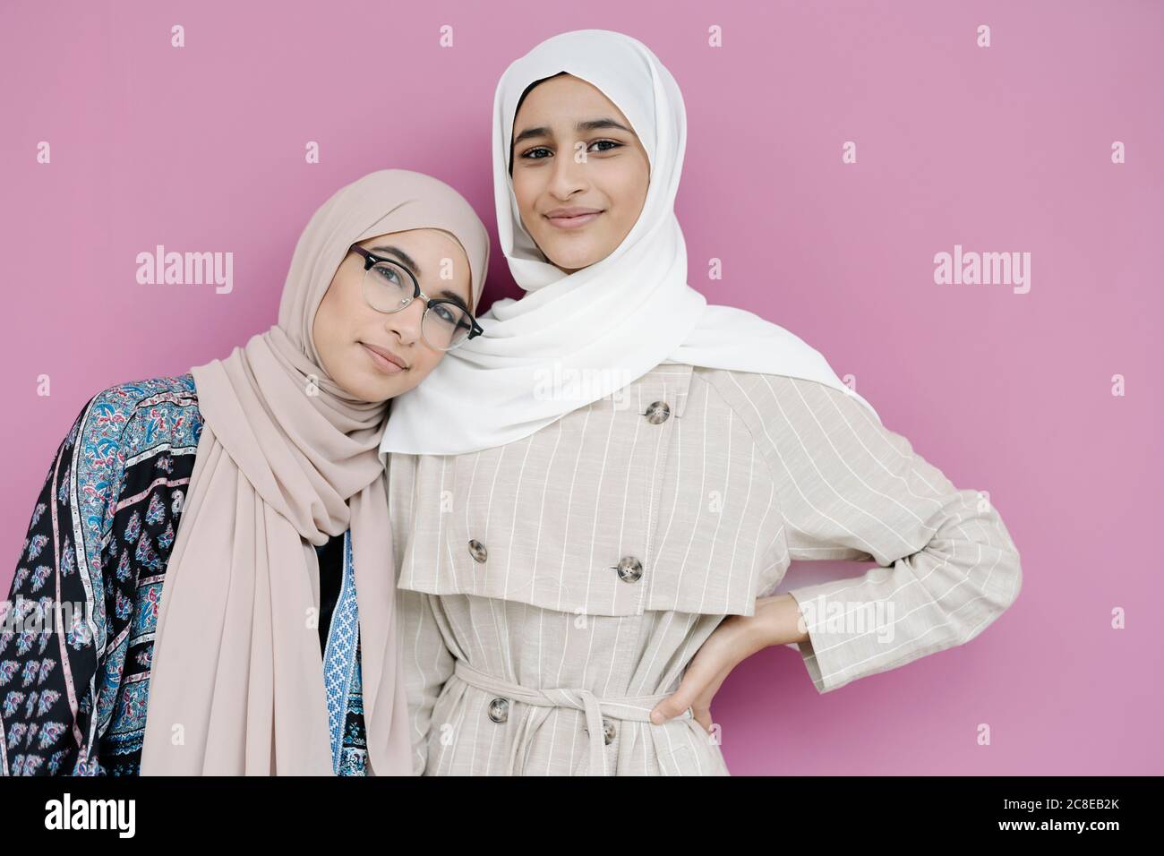 Muslim sisters standing together against purple background Stock Photo ...