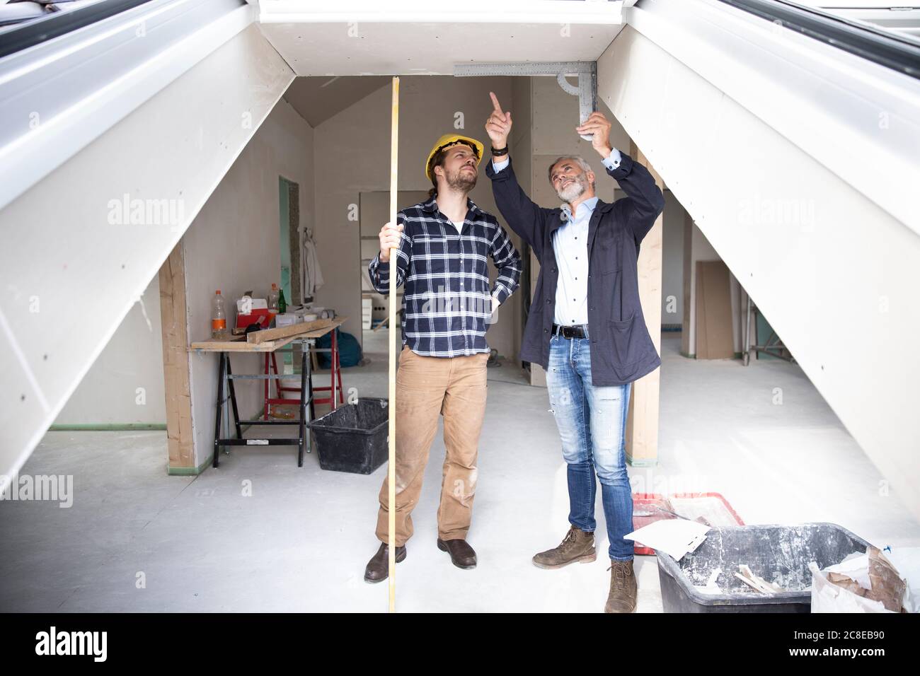 Architect and construction worker discussing about frame in renovating house seen through window ...