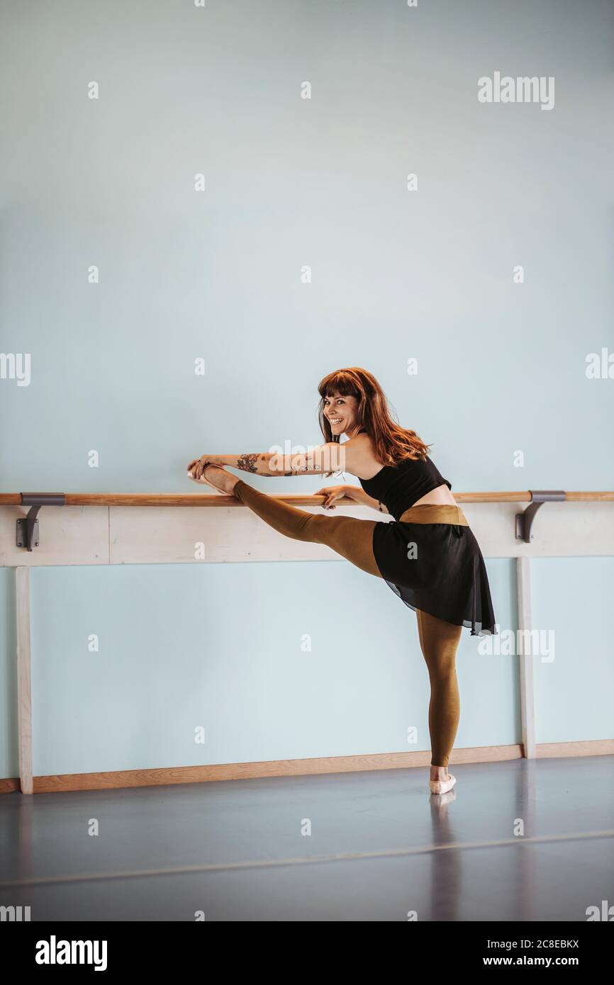 Happy ballet dancer stretching leg in dance studio Stock Photo - Alamy