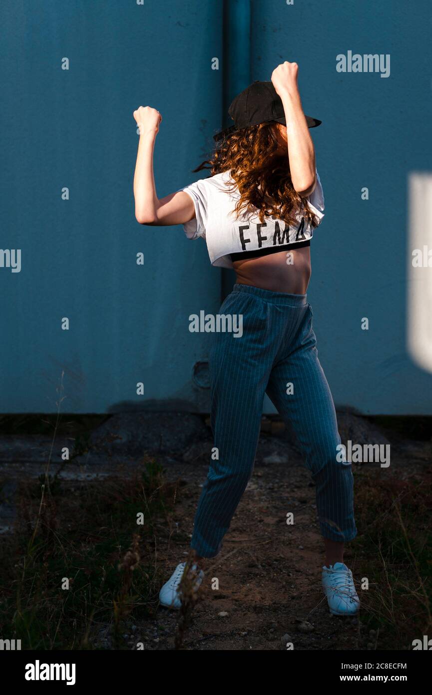 Female hip-hop dancer dancing against wall during sunny day Stock Photo ...