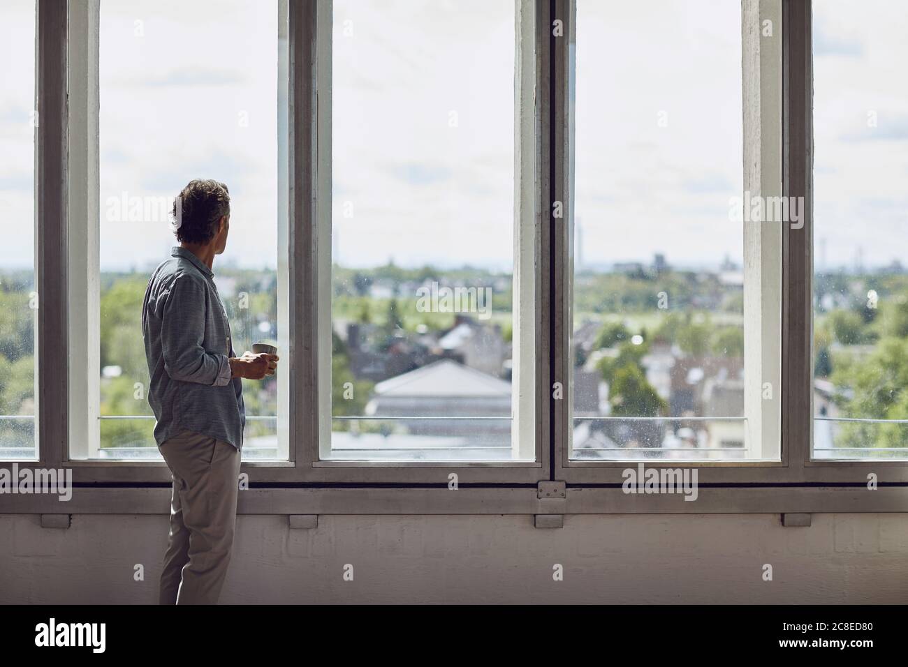 Senior man looking out of window in a loft flat Stock Photo - Alamy